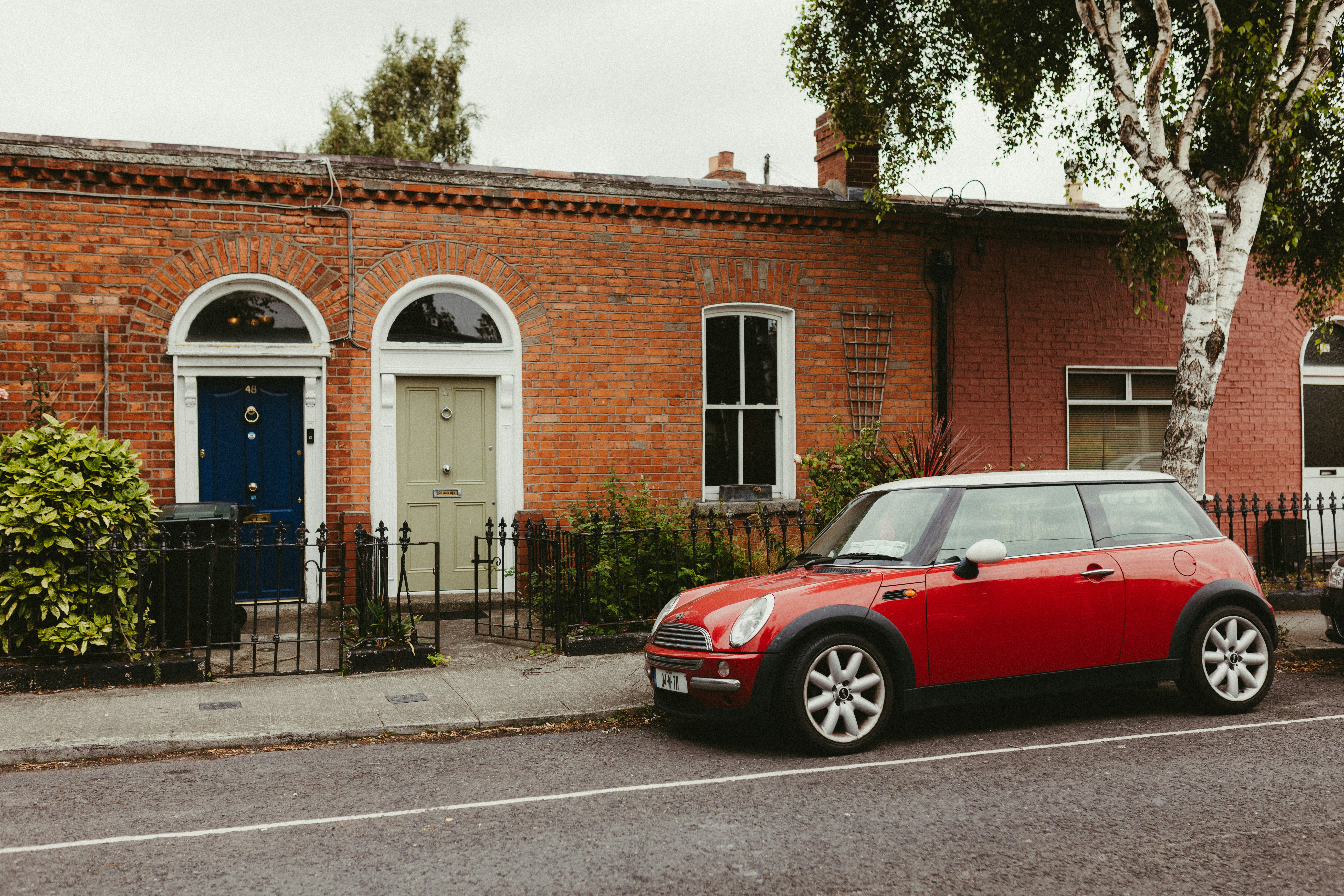 Red Mini Cooper Resting Along a Quiet Brick Row