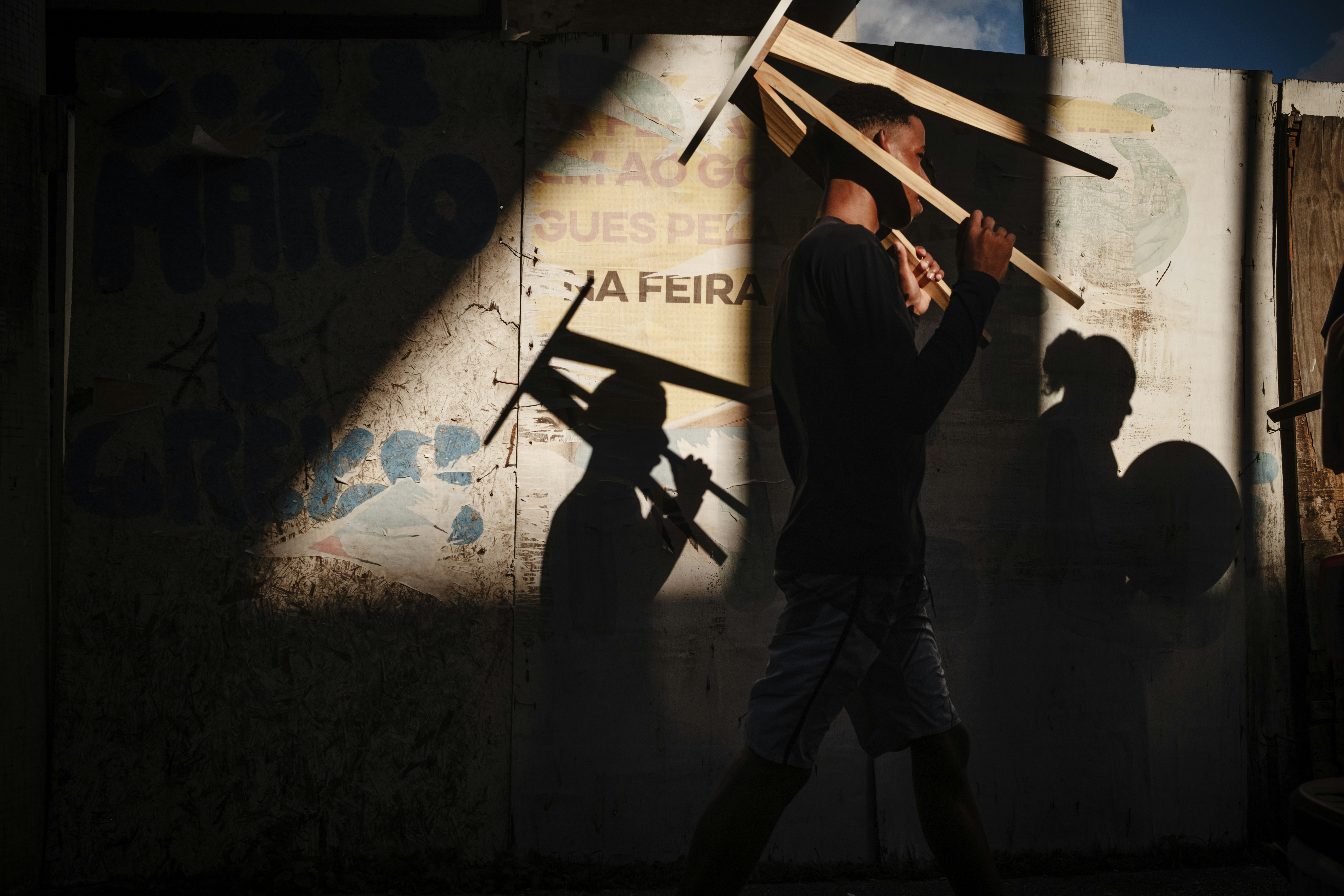 Shaded silhouette of a man with wooden planks across a weathered wall