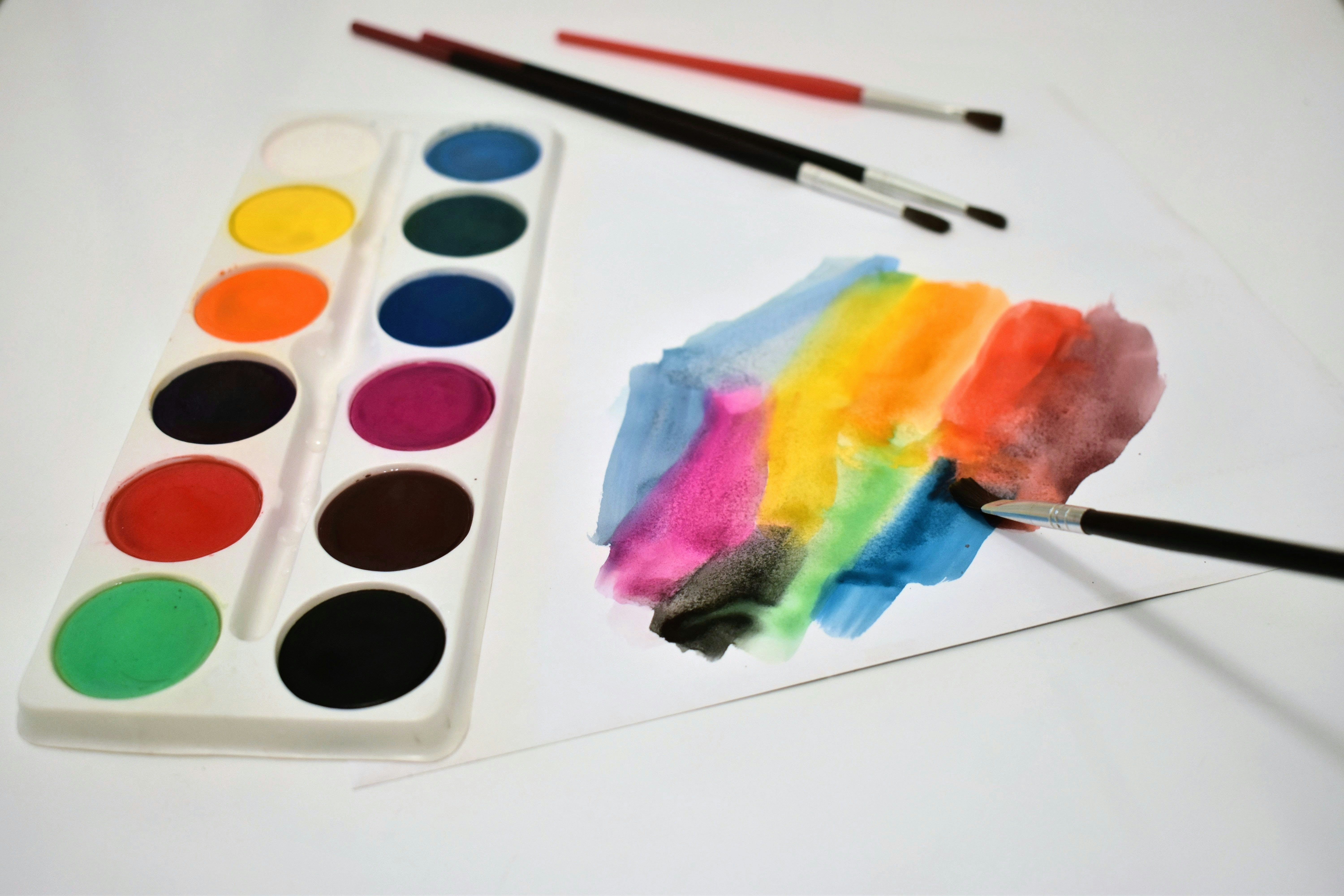 Palette in Focus: Watercolor Blends and Brushes on White Workspace