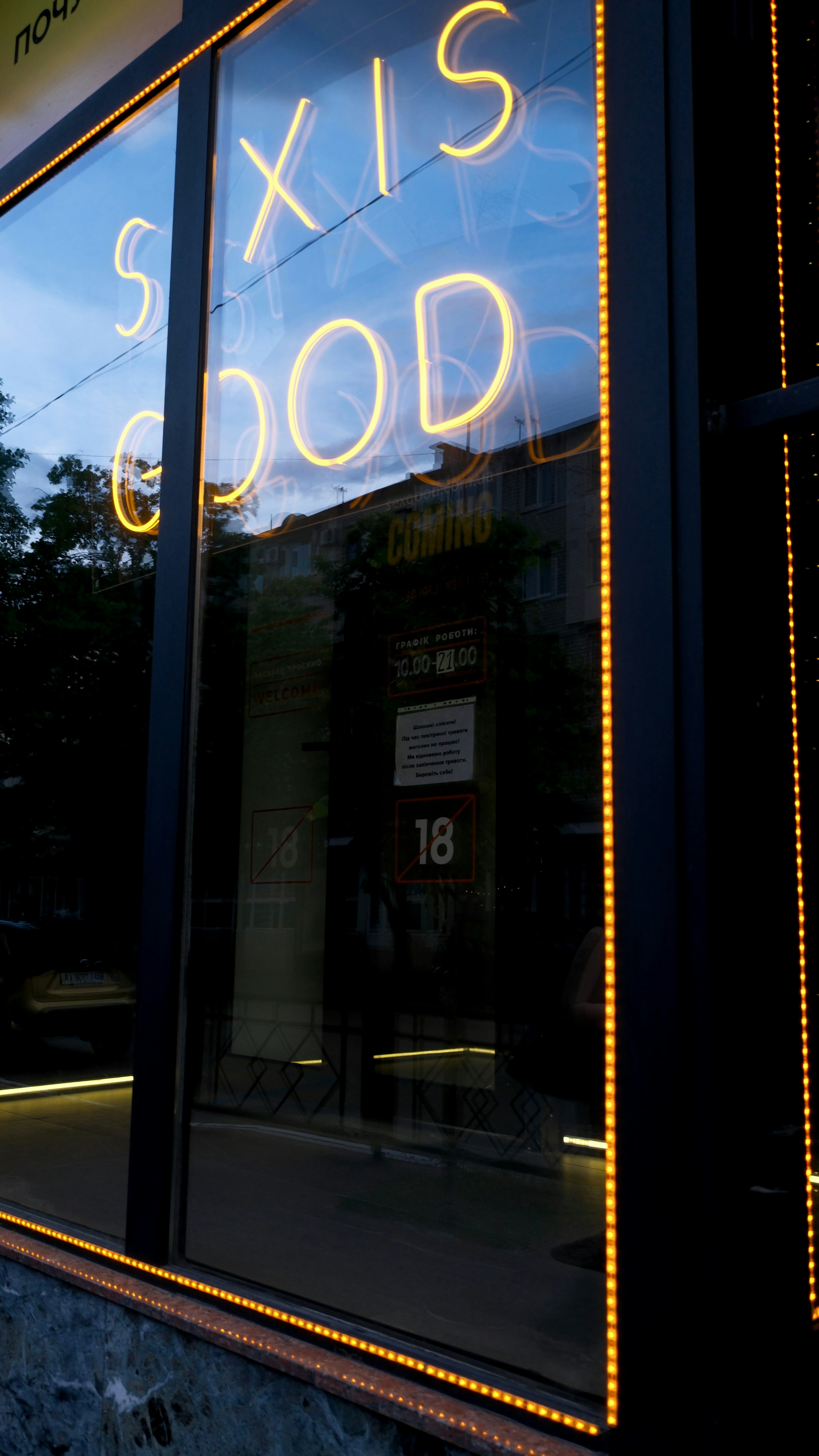 Neon Glow on Glass: Streetfront Sign through a Darkened Window