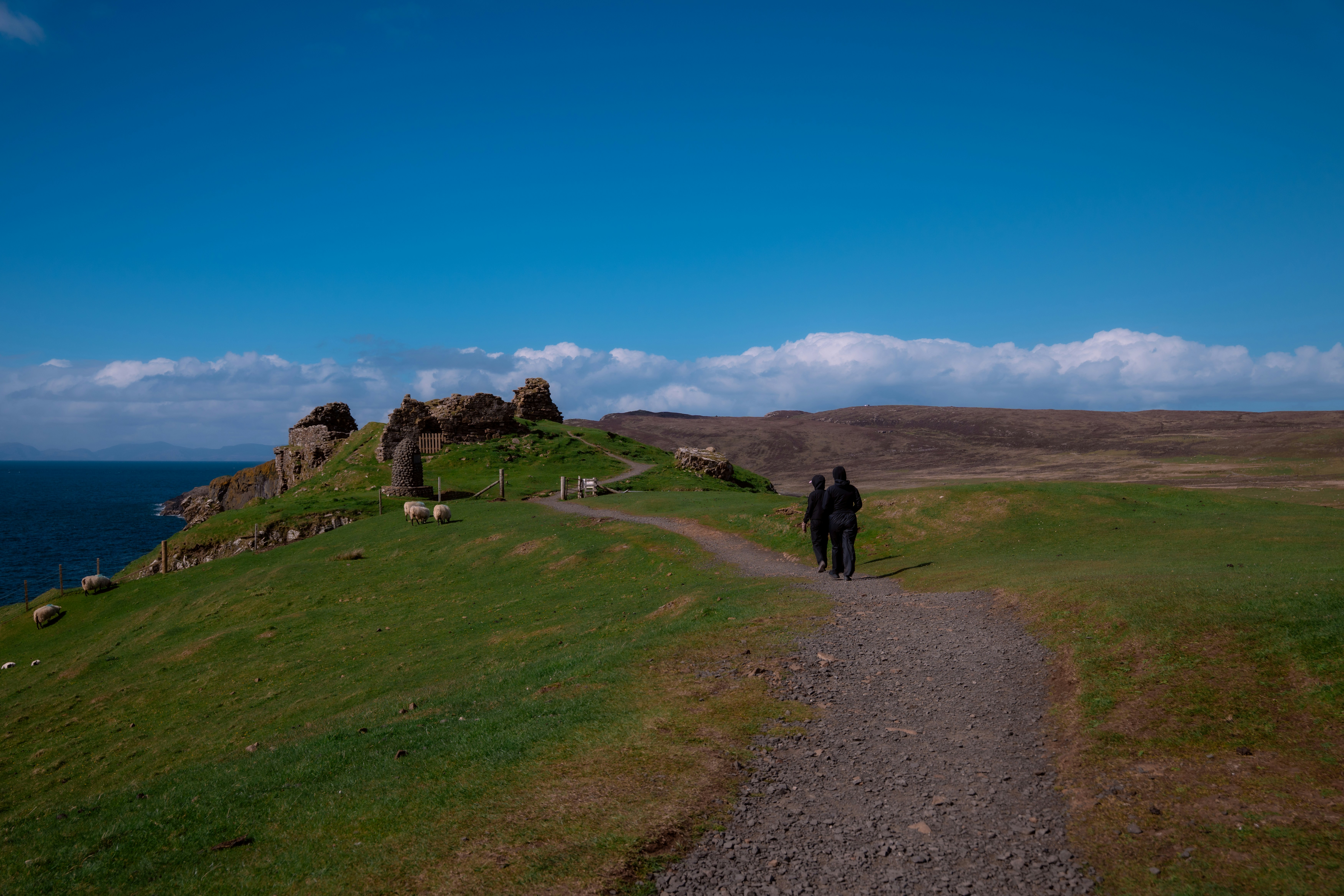 Path to the Clifftop: Two hikers toward the distant ruin