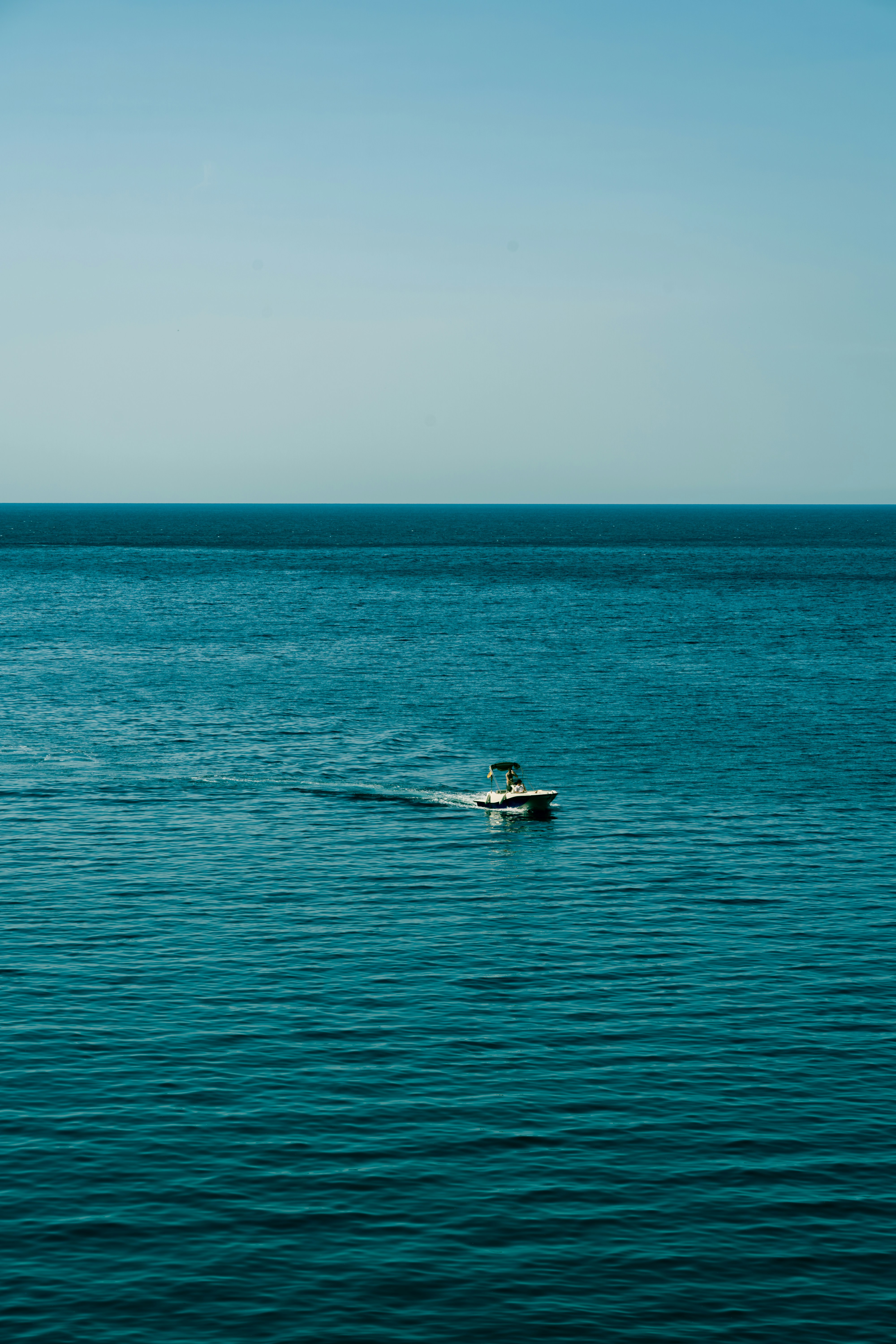 Mid-Sea Silhouette: A Lone Boat Cutting Through Quiet Blue