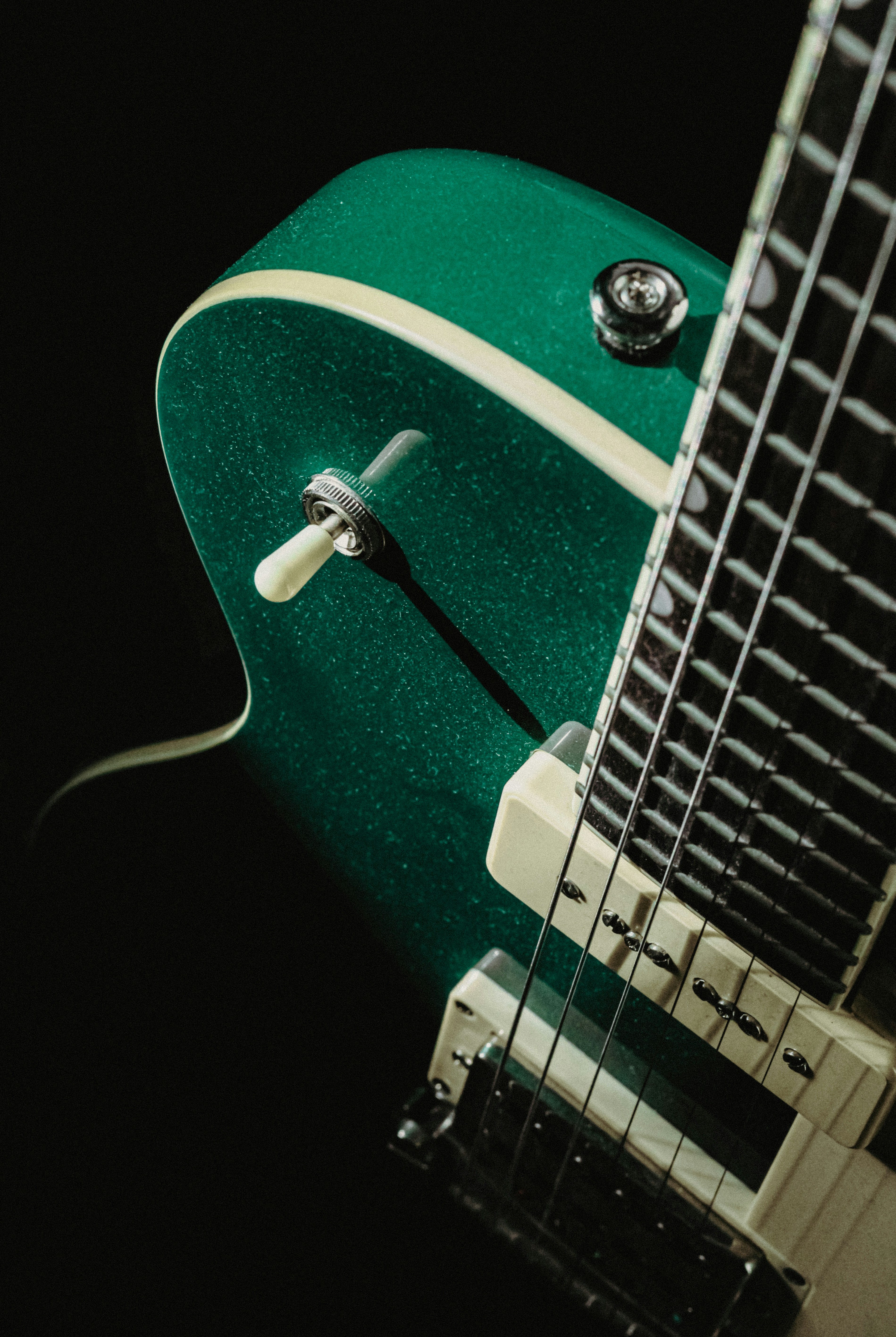 Emerald Chell: A Close-Up on a Green Tele-Style Guitar in Focused Night Light