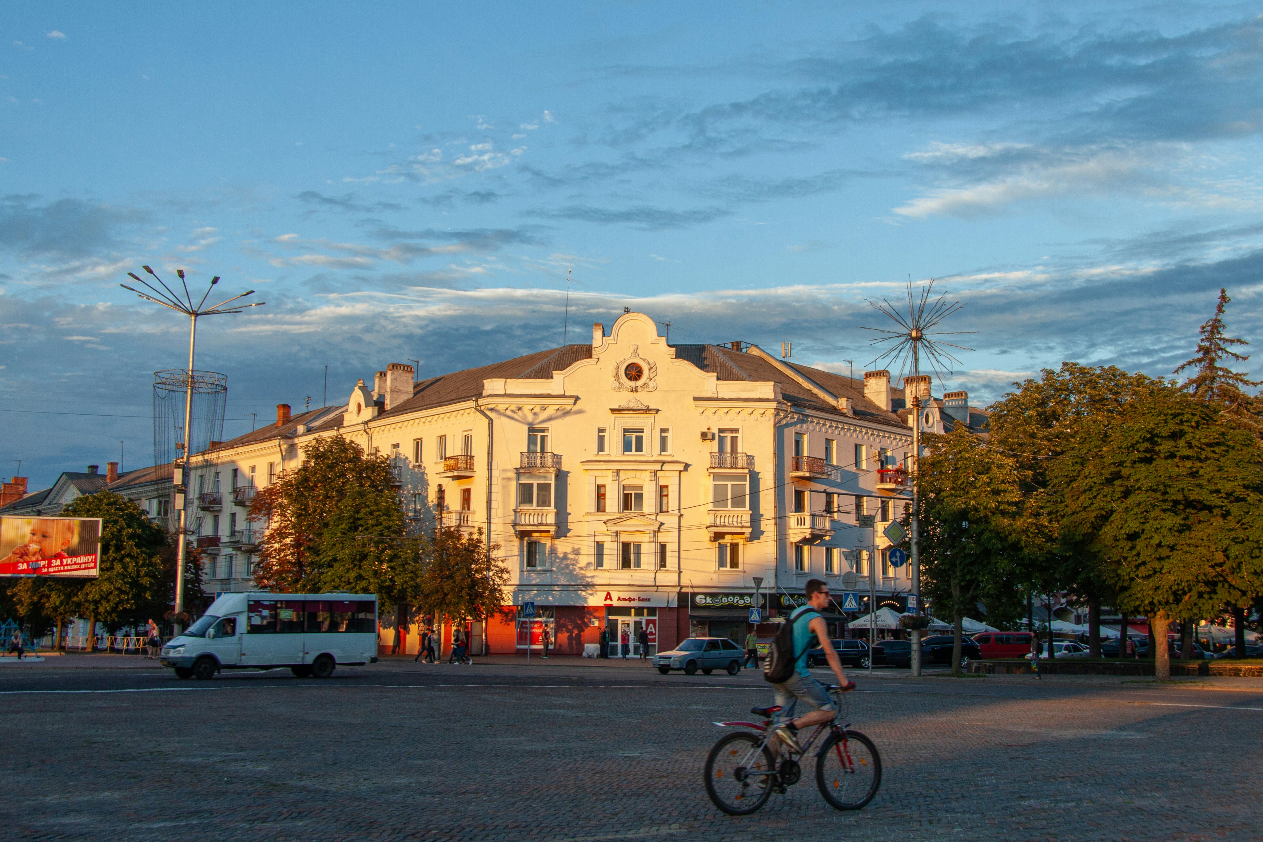 Sunlit Facade and Moving Cyclist on a Quiet Town Square