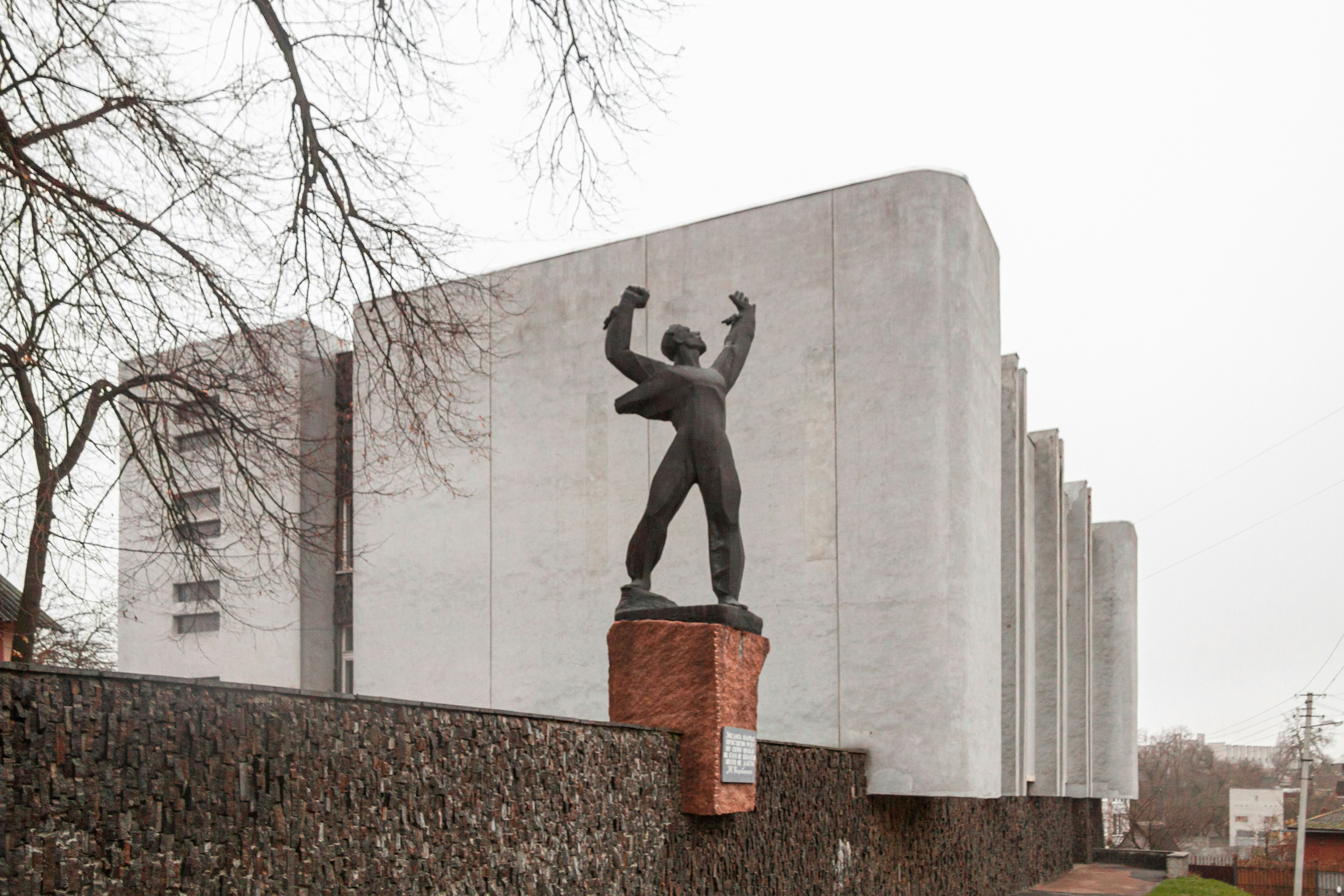 Statue on brick plinth against stark modern building