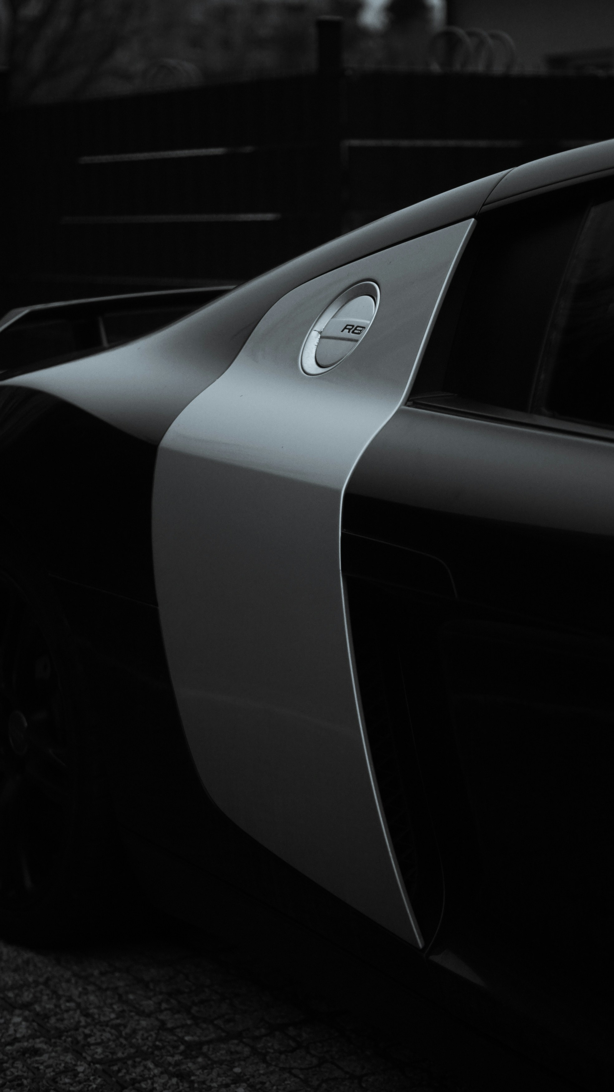 Side view of a dark audi r8 with silver blade.