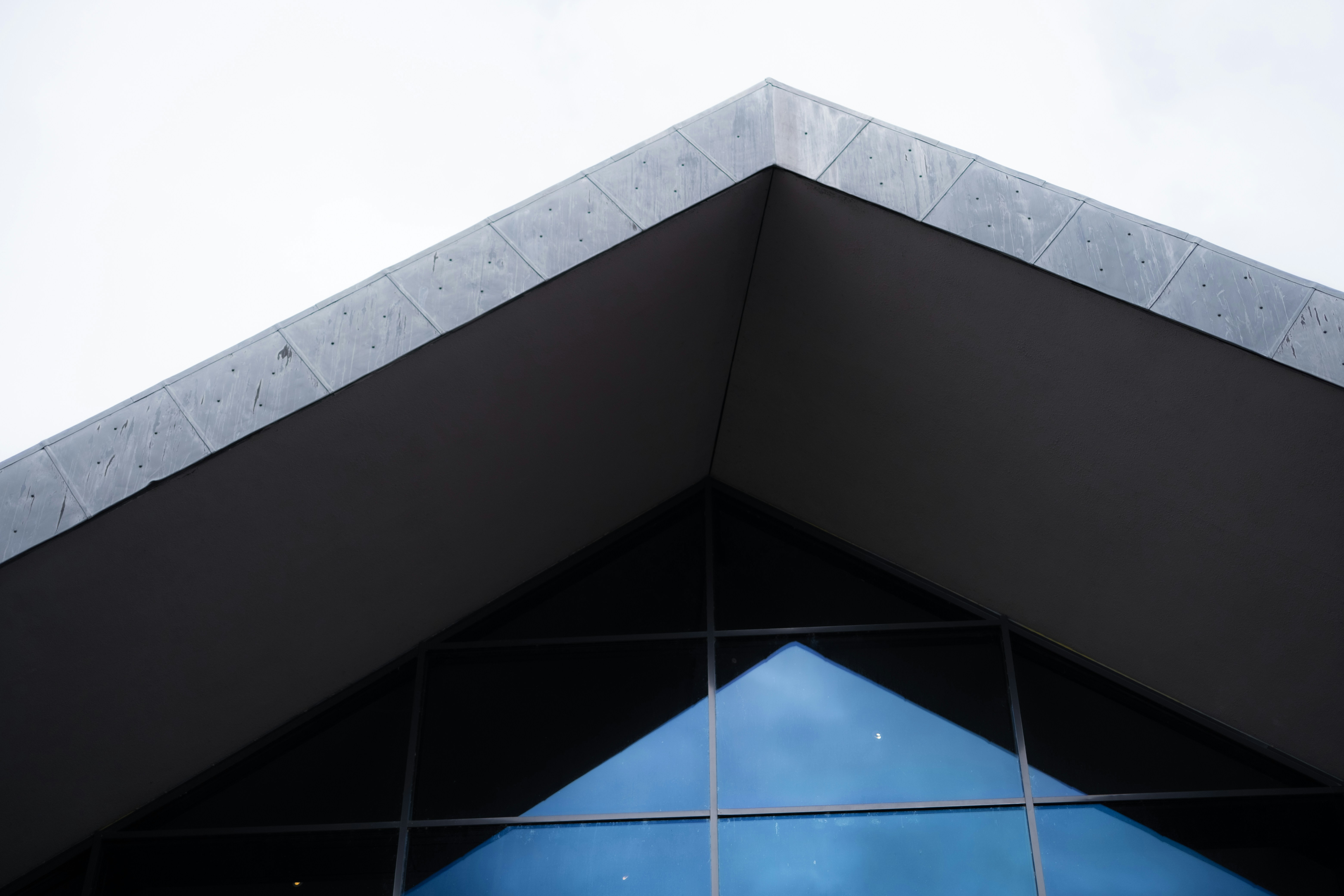 Converging Roofline: A Sharp Peak Above a Glass Facade