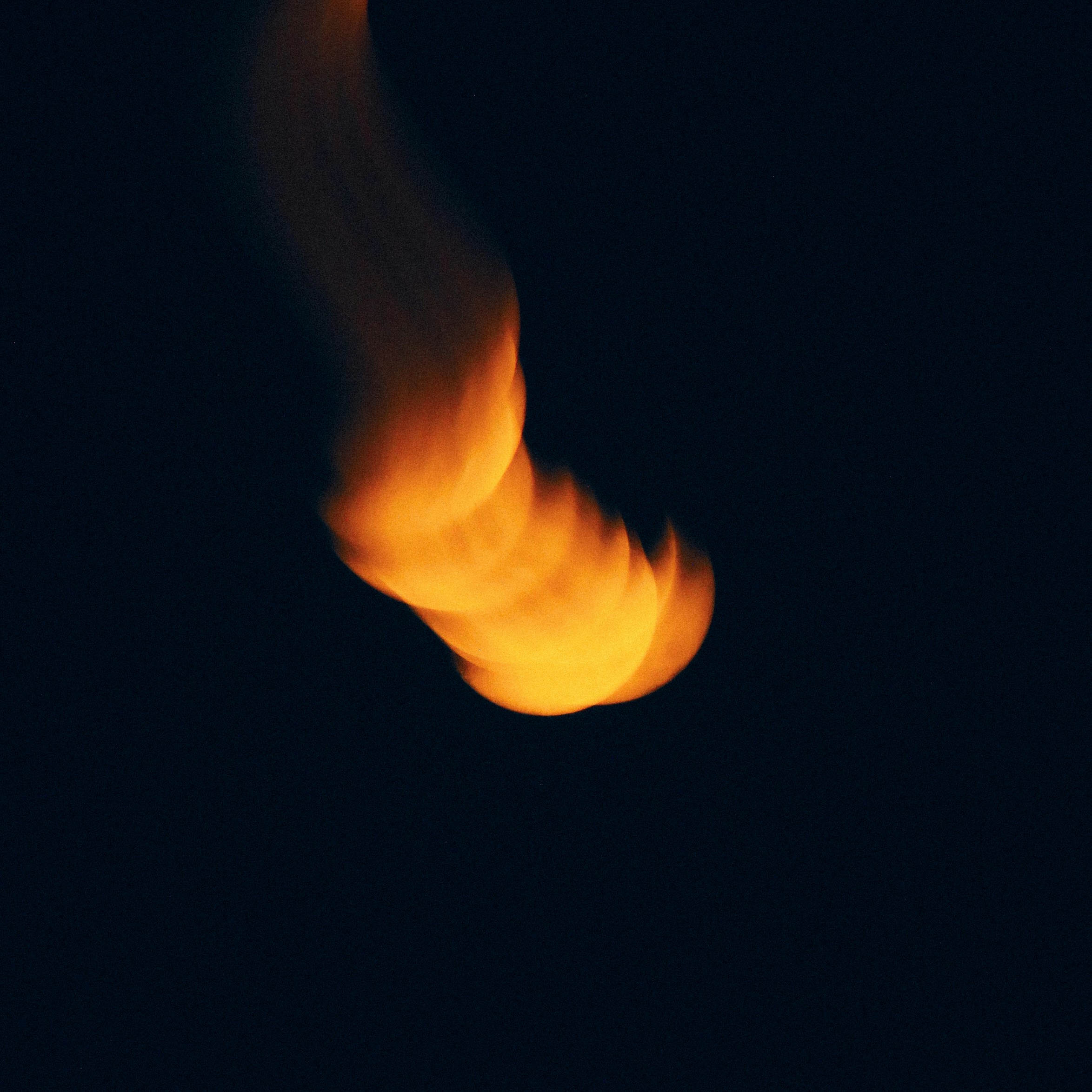 Tongue of Fire: a solitary flame curling through darkness