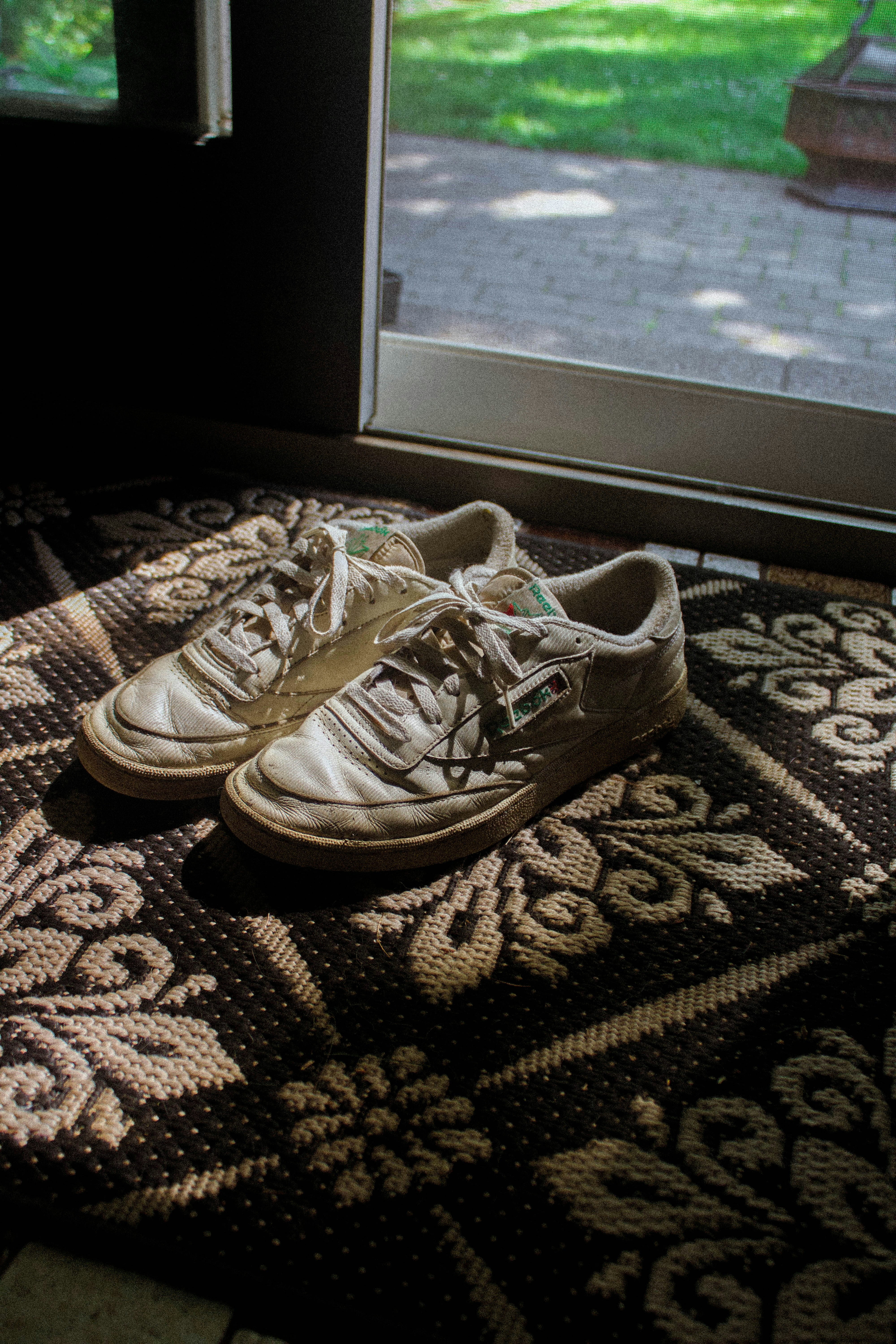 Echoes of the Hall: Worn Sneakers Resting on a Patterned Rug
