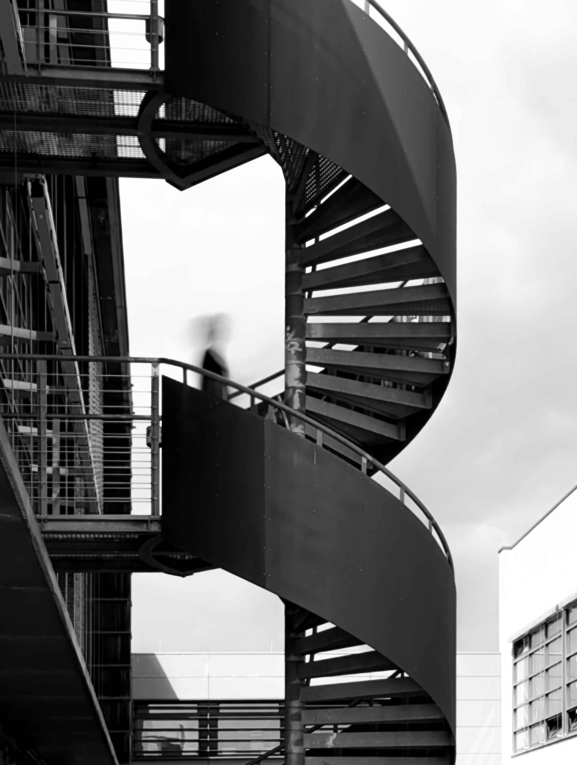 Spiral Iron: A Ghostly Figure on the Metal Staircase