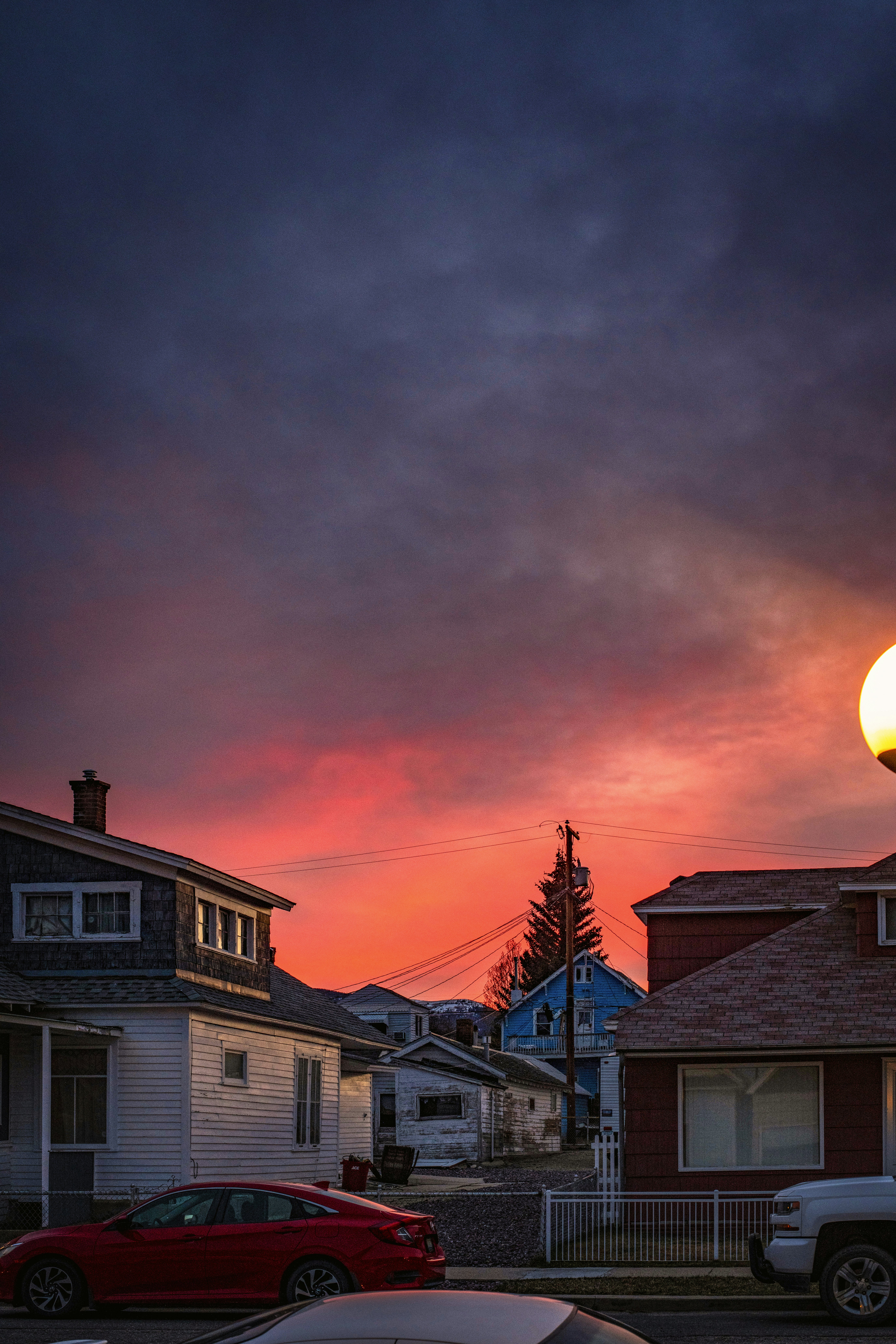 Sunset Over Quiet Suburb: A Red Car, Warm Sky, and Painted Houses