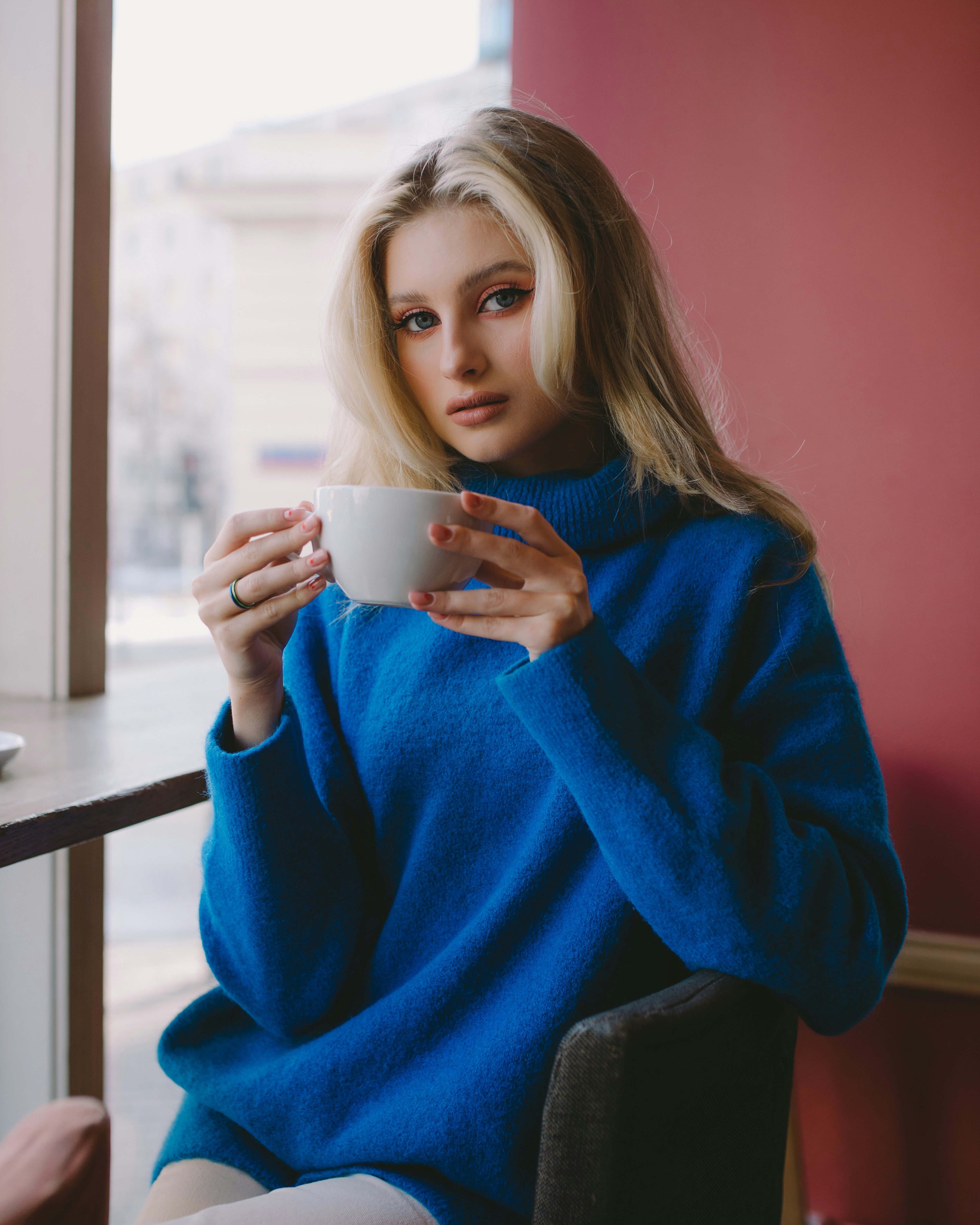 Cozy Café Confidence: A Blonde in a Bold Blue Sweater with a Quiet Cup
