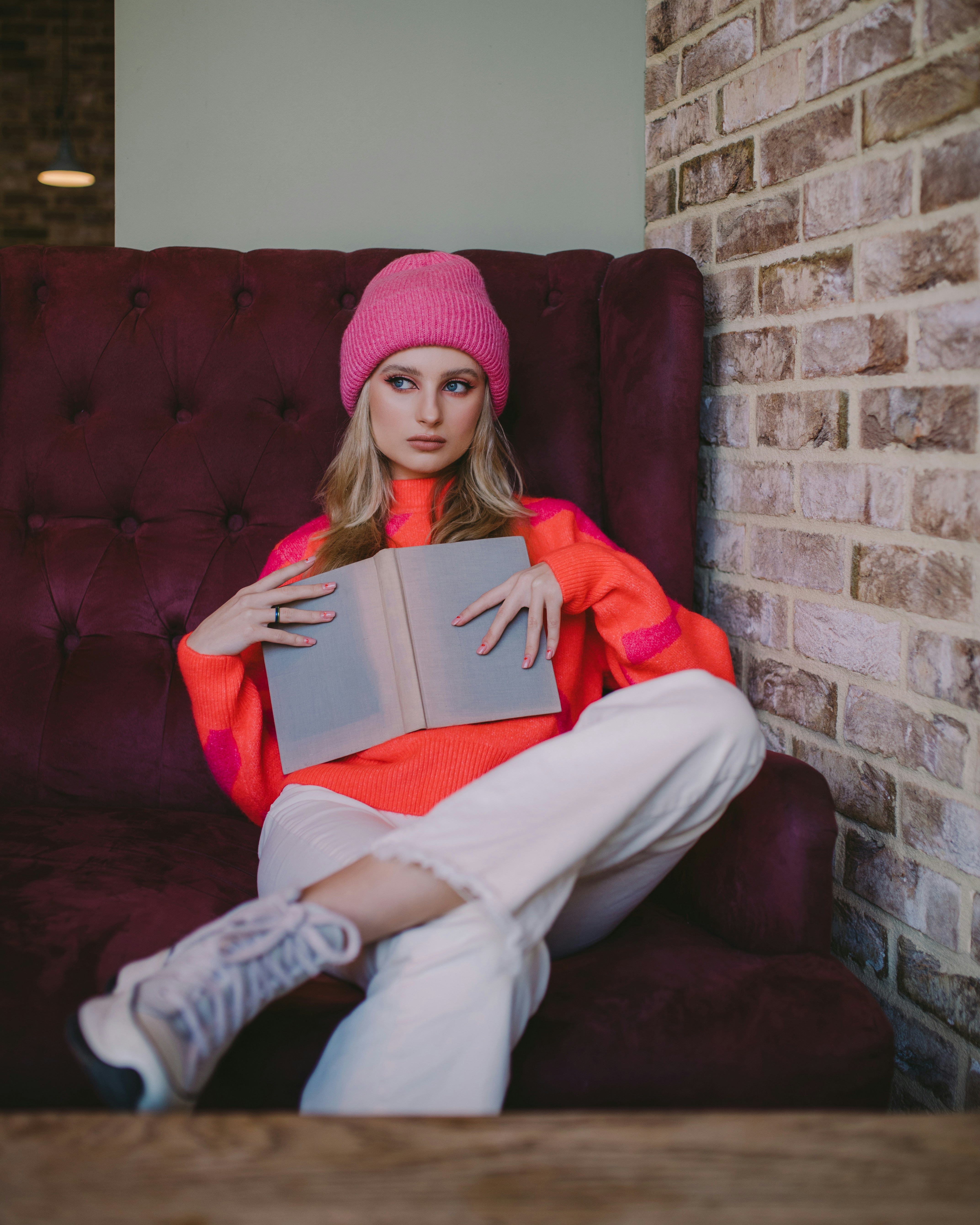 Cozy Confidence: Neon Knit and Open Book on a Velvet Armchair