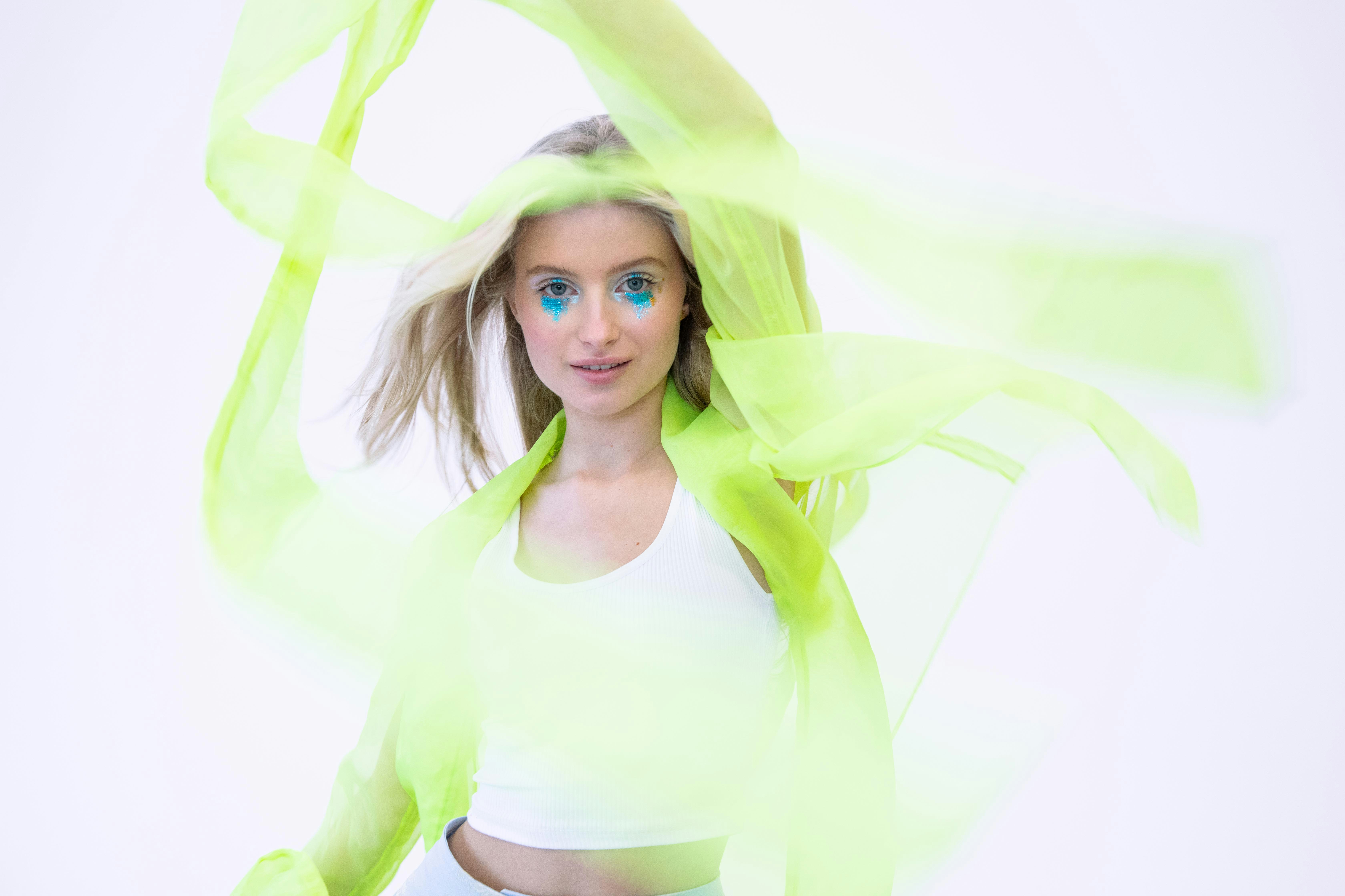Neon scarf dancer: a bright rush of motion around a centered gaze