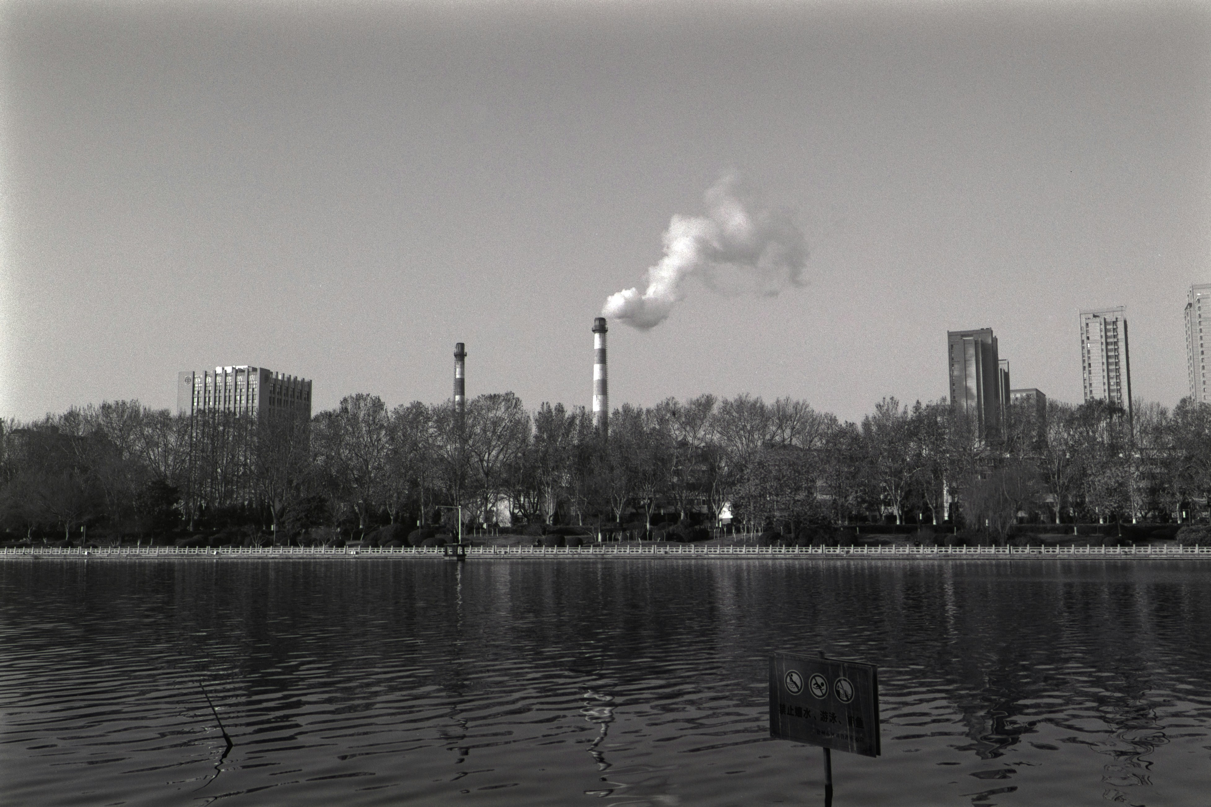 Industrial Horizon: Smoke and Water Reflections in Monochrome