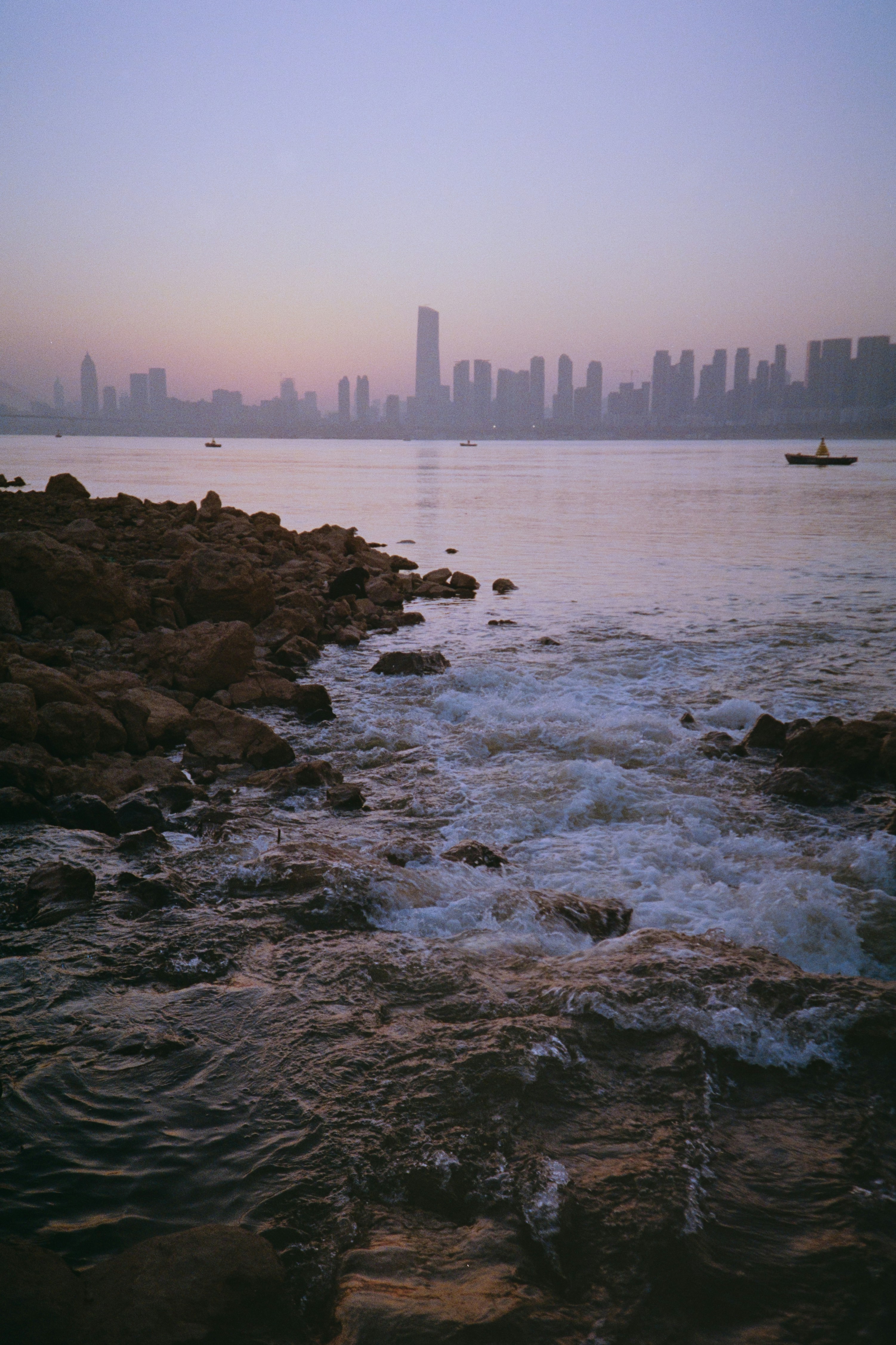Rocks and Skyline at Dusk: A Quiet Confluence of Shore and City