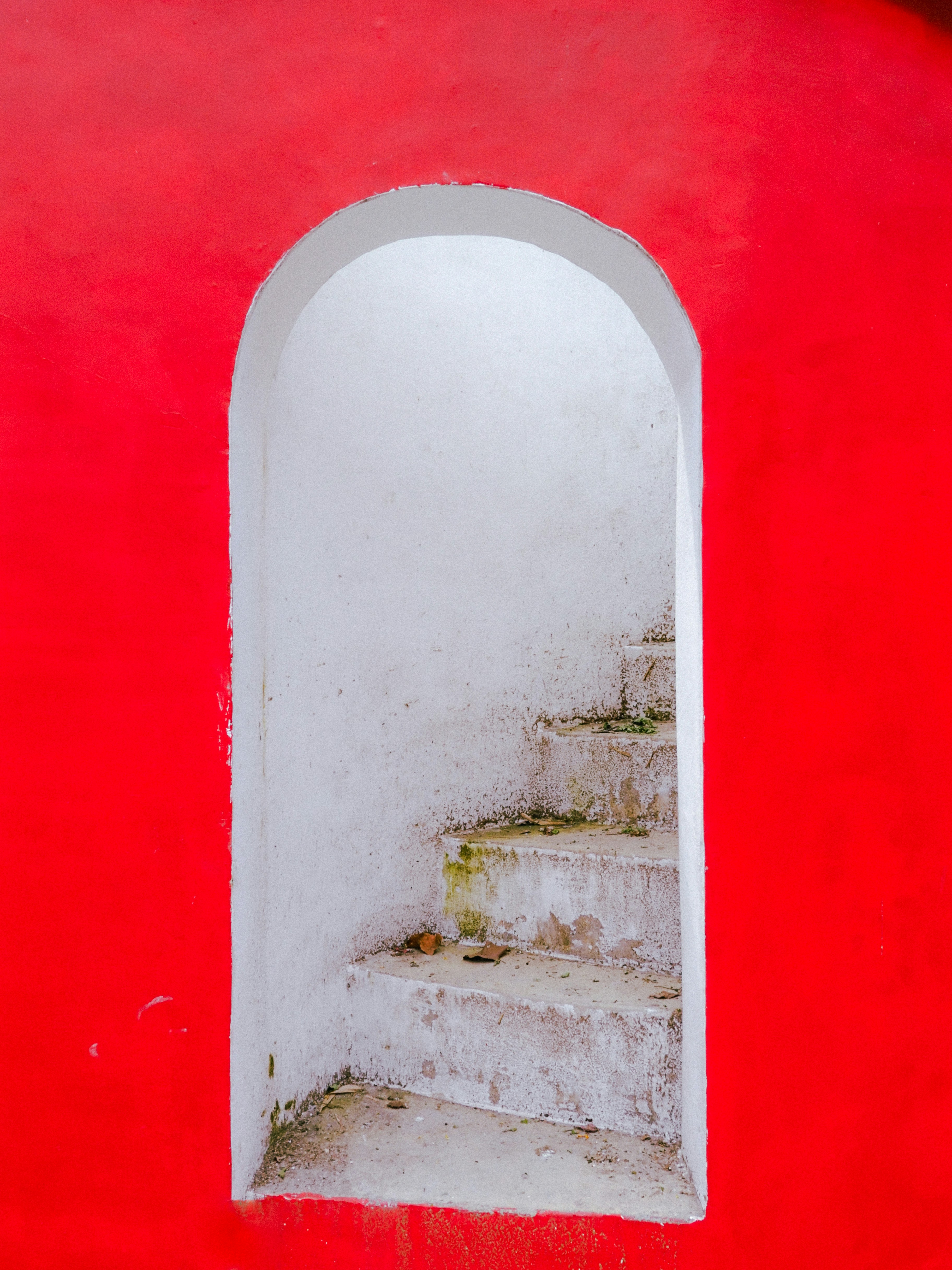 Red Portal to Quiet Steps: A Stairway Through a White Arch