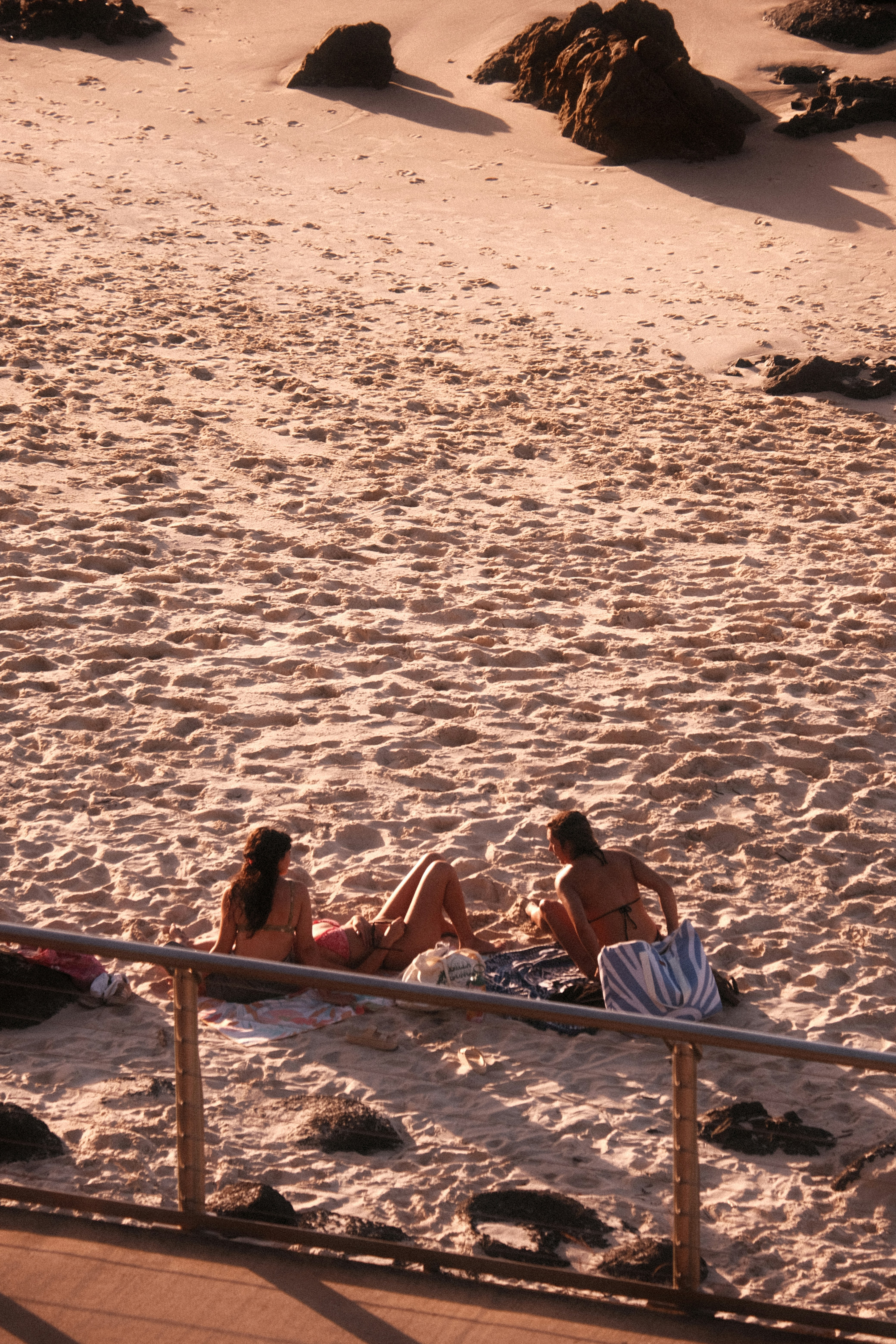 Sunlit Beach Respite: Two Relaxed Souls by the Rail