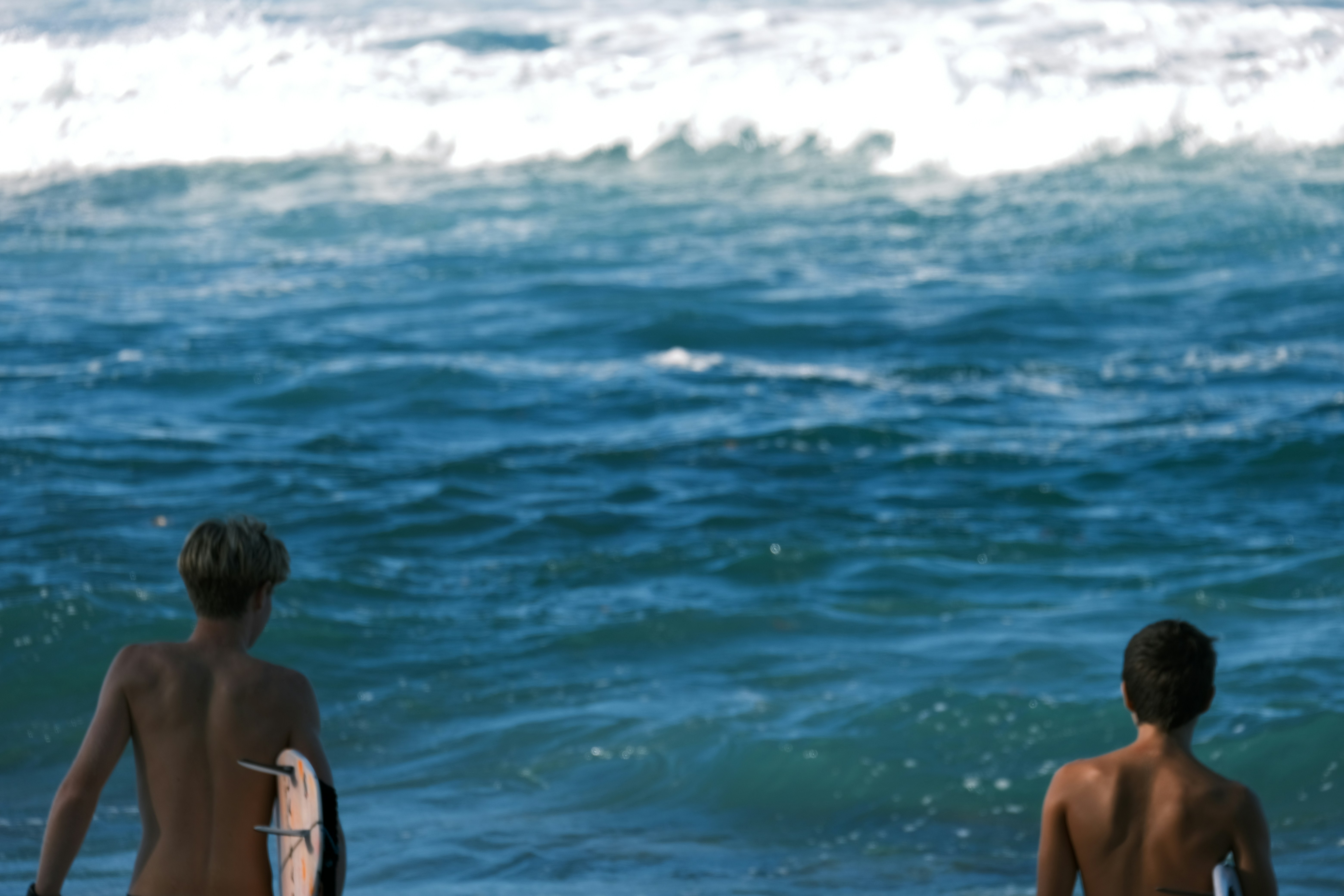 Two Youthful Surfers Stand Their Ground at Distant Break