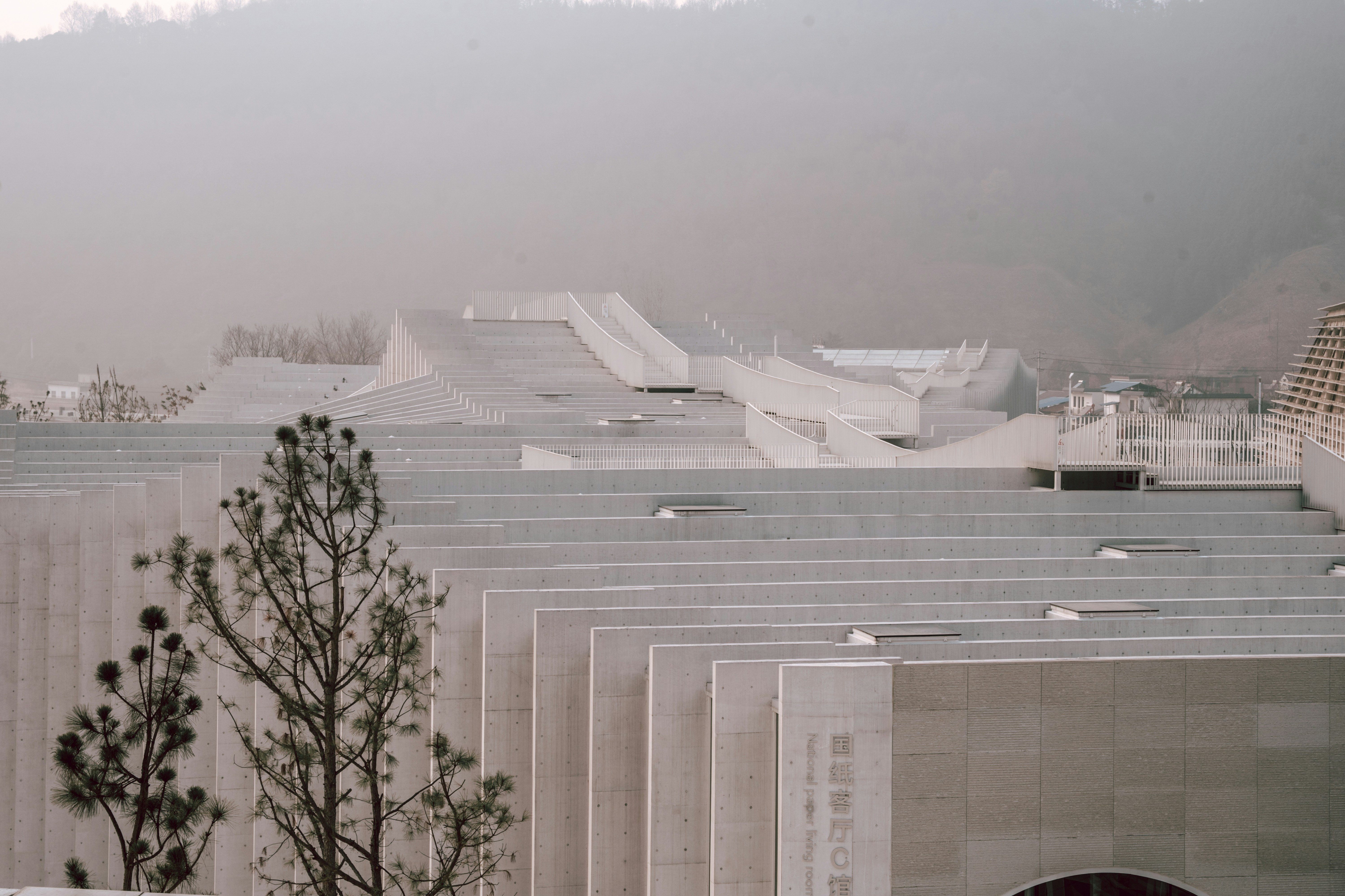 Monolithic campus terraces fade into misty hills