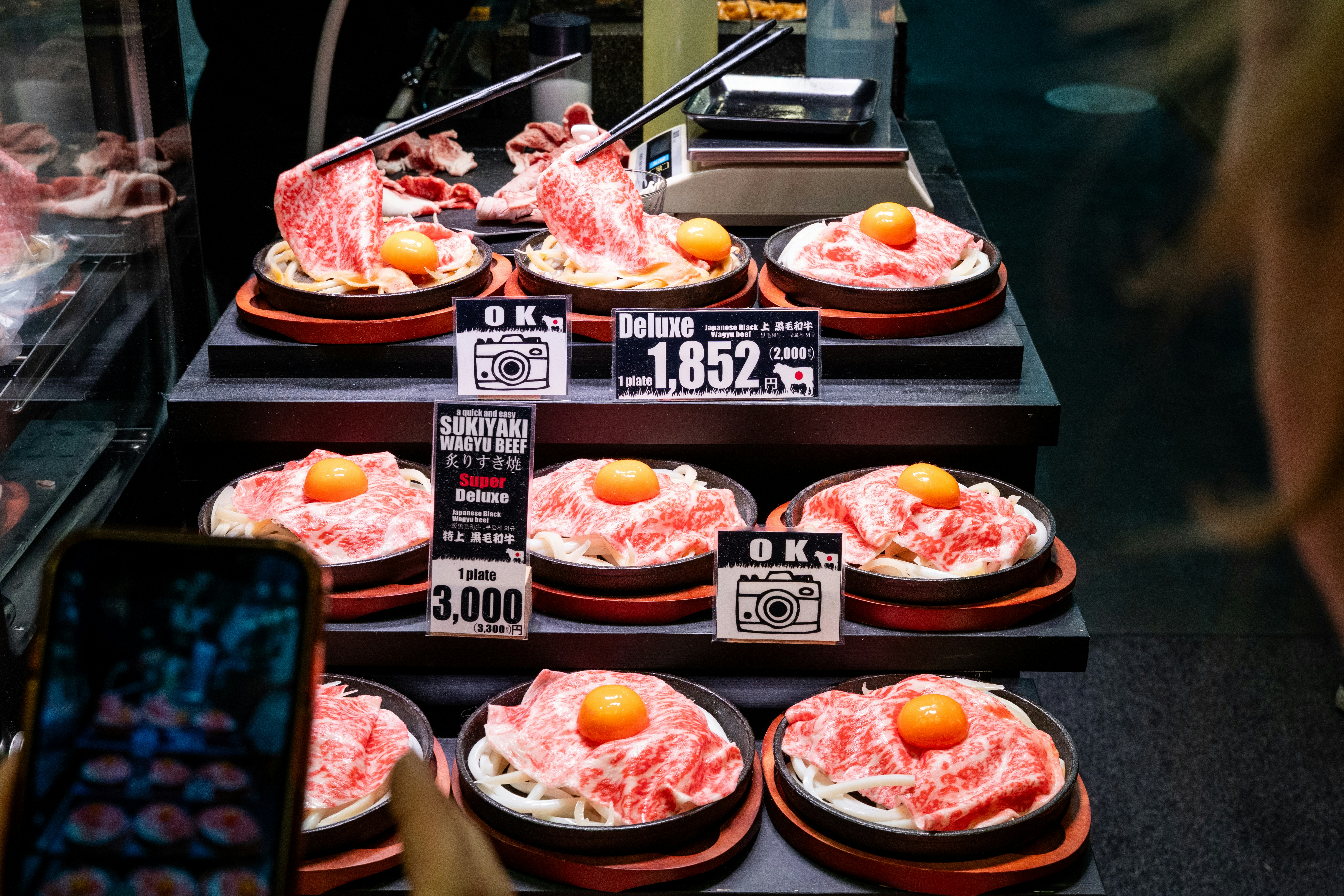 Raw wagyu beef and egg yolks displayed in a market.