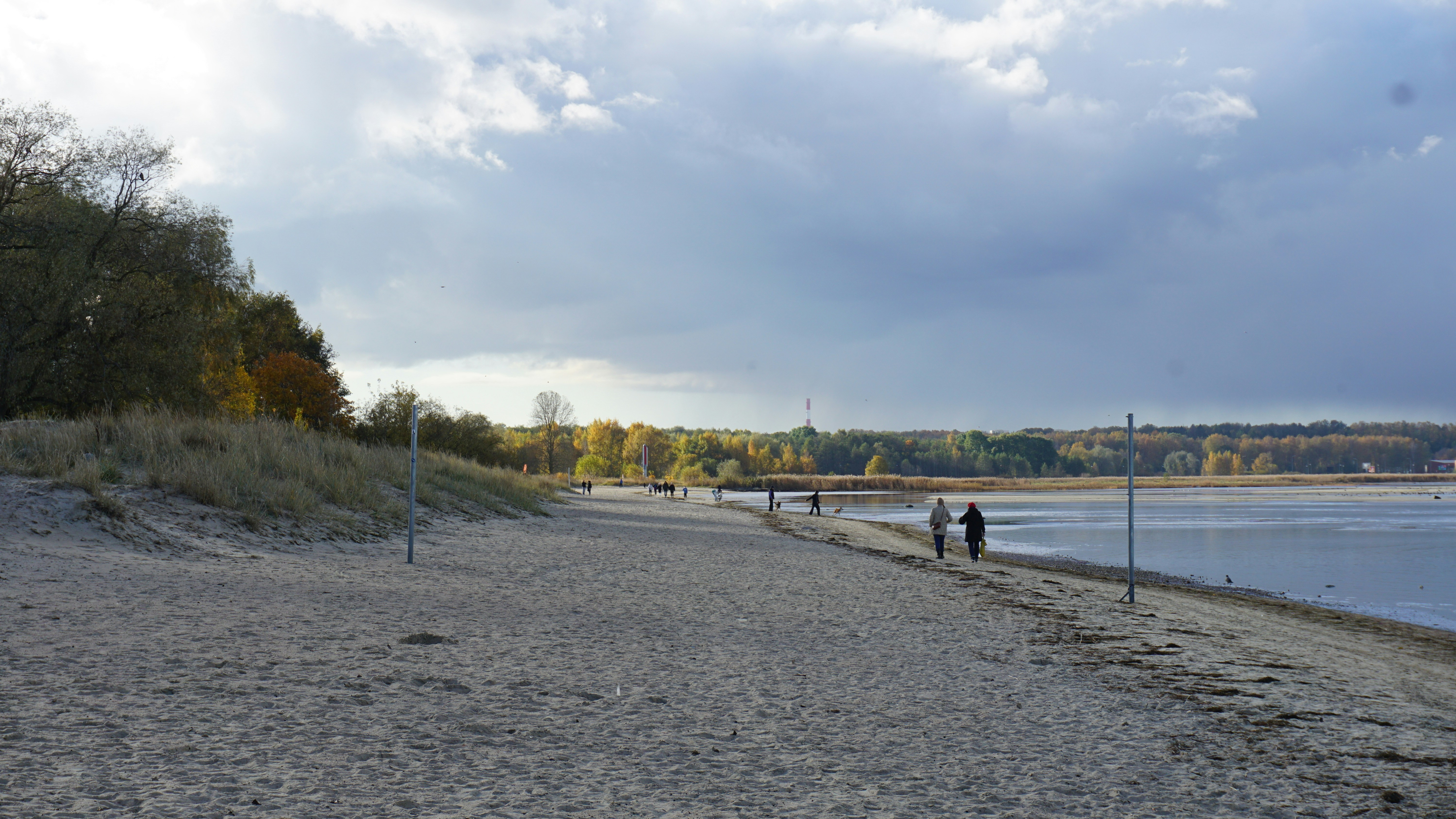 Autumn shoreline: distant walkers on a quiet sand beach