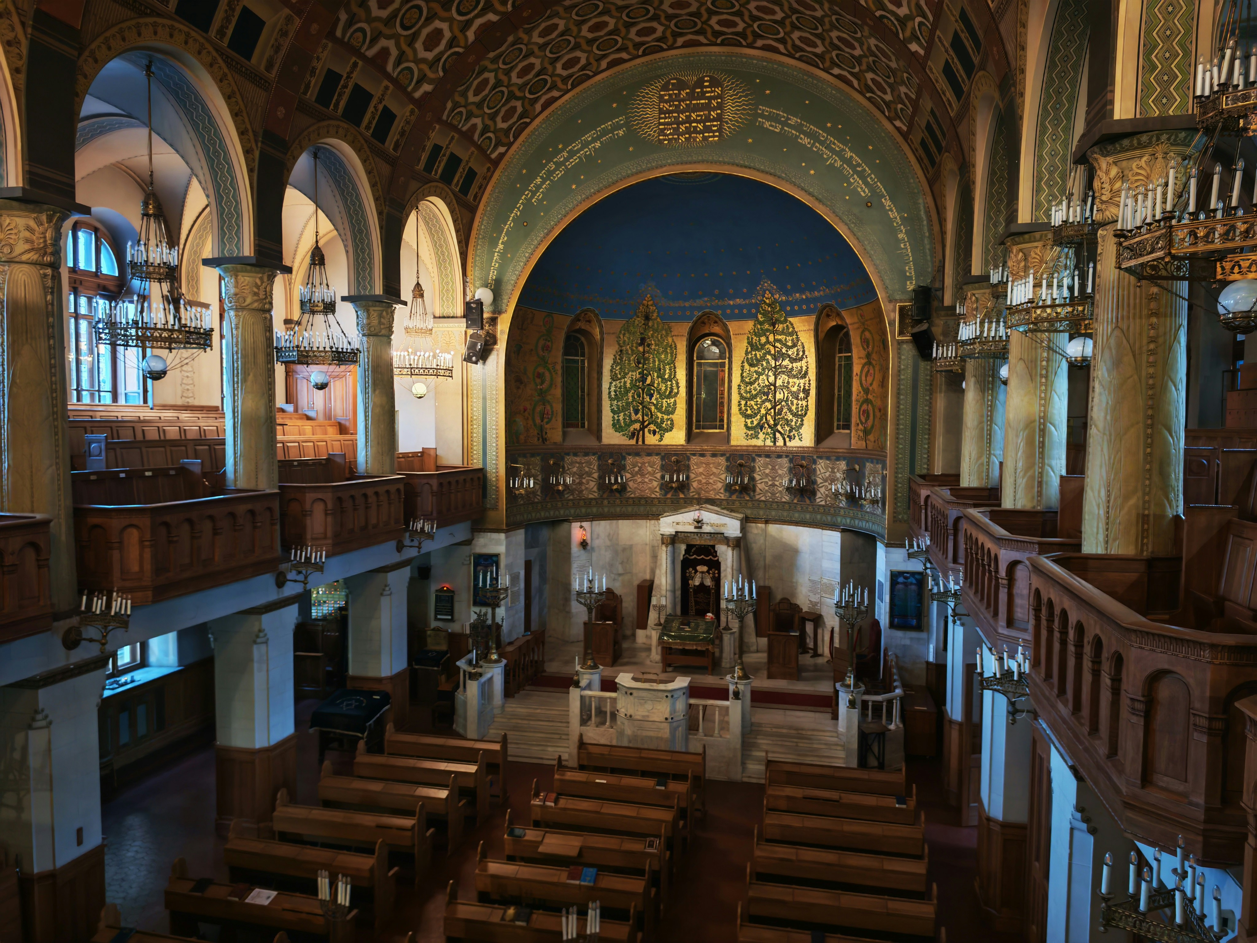 Interior of a grand church with ornate arches and a central nave, visible chandeliers and sculpted altar in the distance; a serene, cathedral-like space captured to emphasize symmetry and warm color tones.