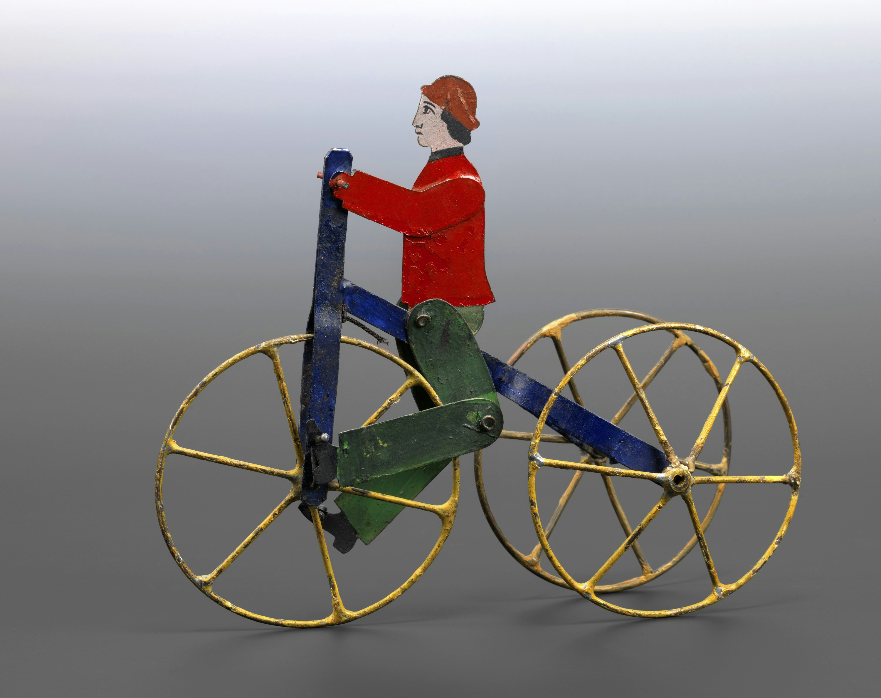 Red-Top Rider on a Vintage Tricycle: A Toy Scene in Flight
