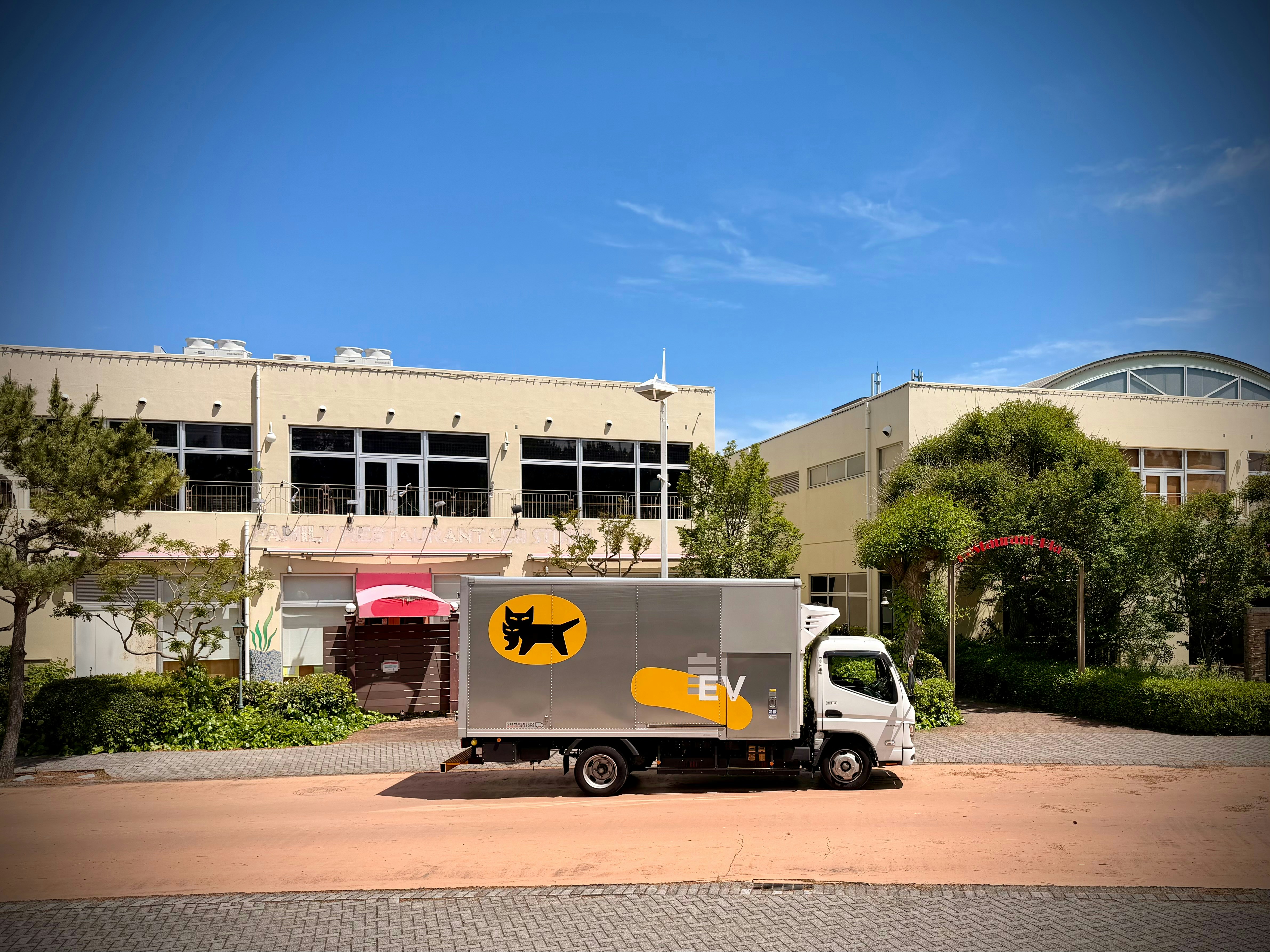 Delivery Truck with Cat Silhouette Passing a Modern Campus