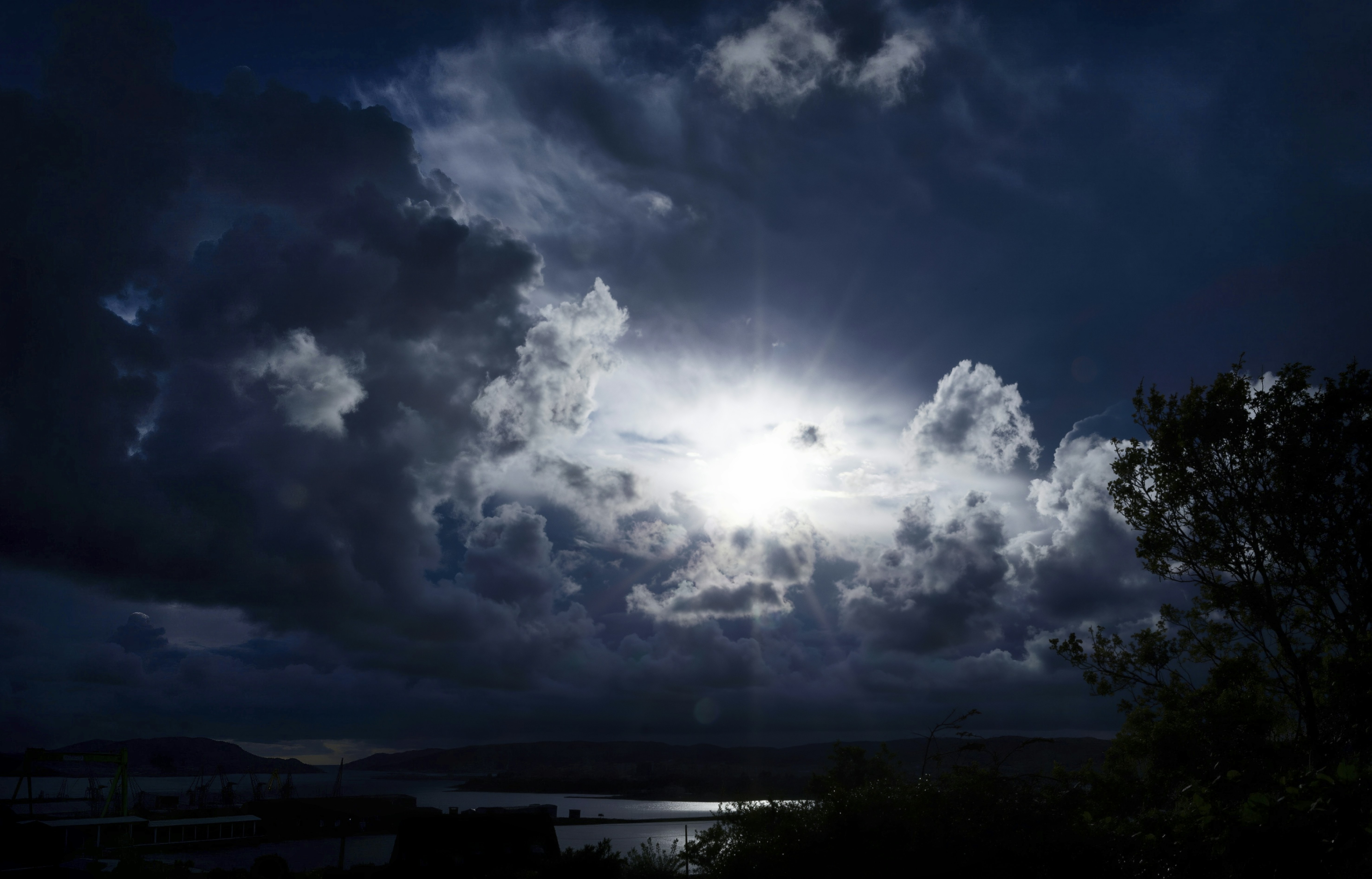 Sunlit Break in the Cloud Wall over a Silhouetted Landscape