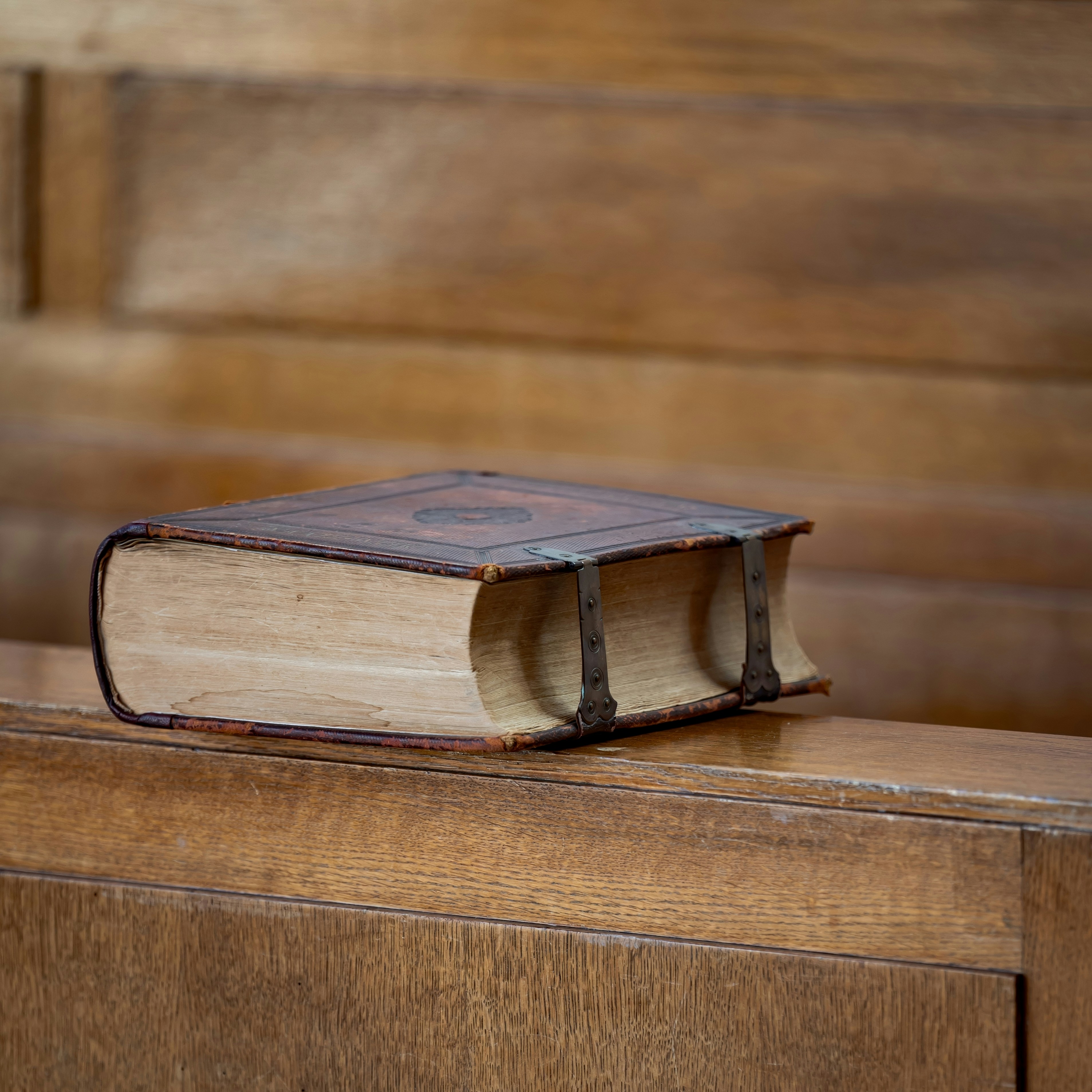An antique book with metal clasps on a wooden surface.