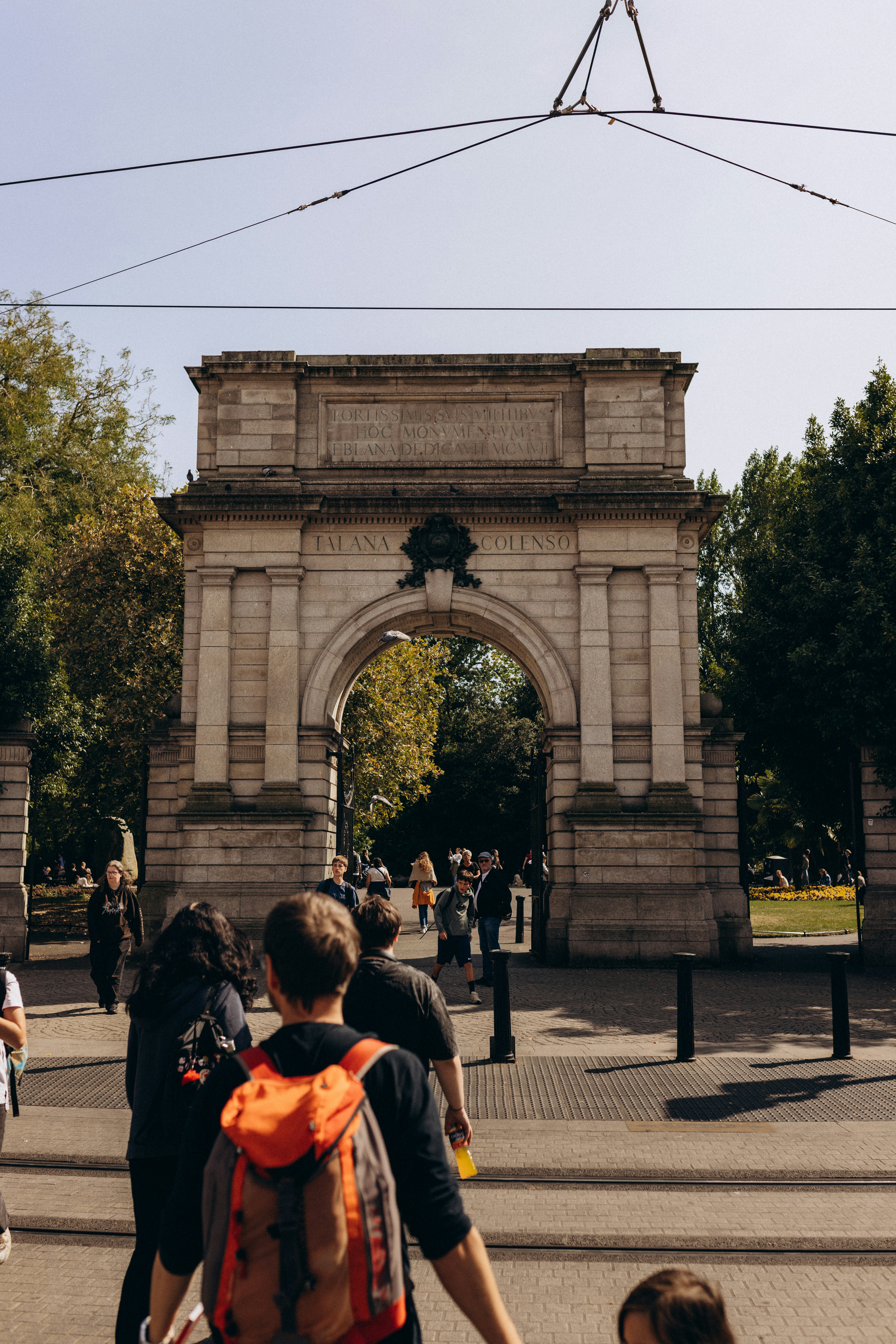 Gateway of the Park: People Entering Through a Stone Arch