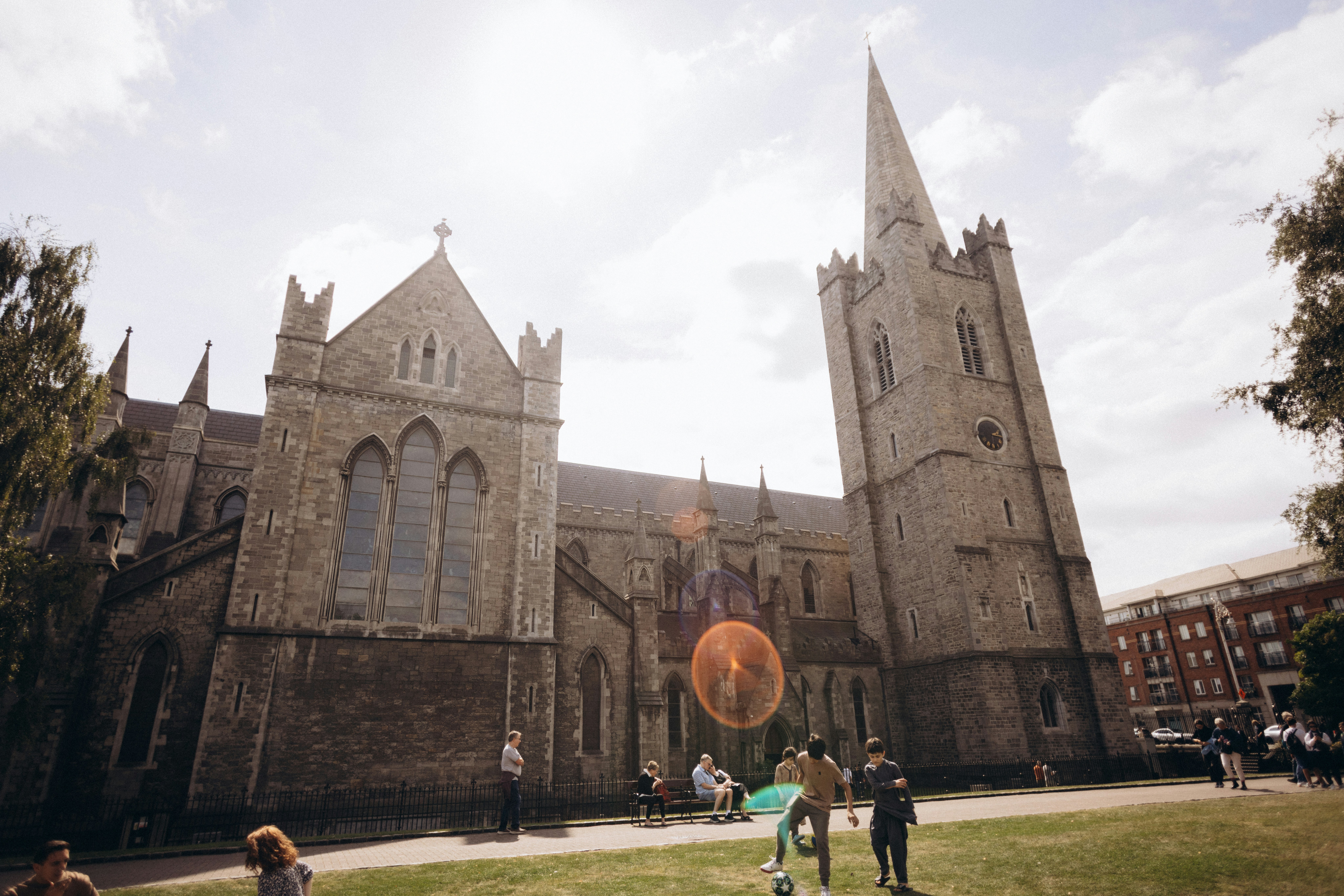 Stone Cathedral Quadrangle: Visitors on the Lawn under a Sunlit Façade