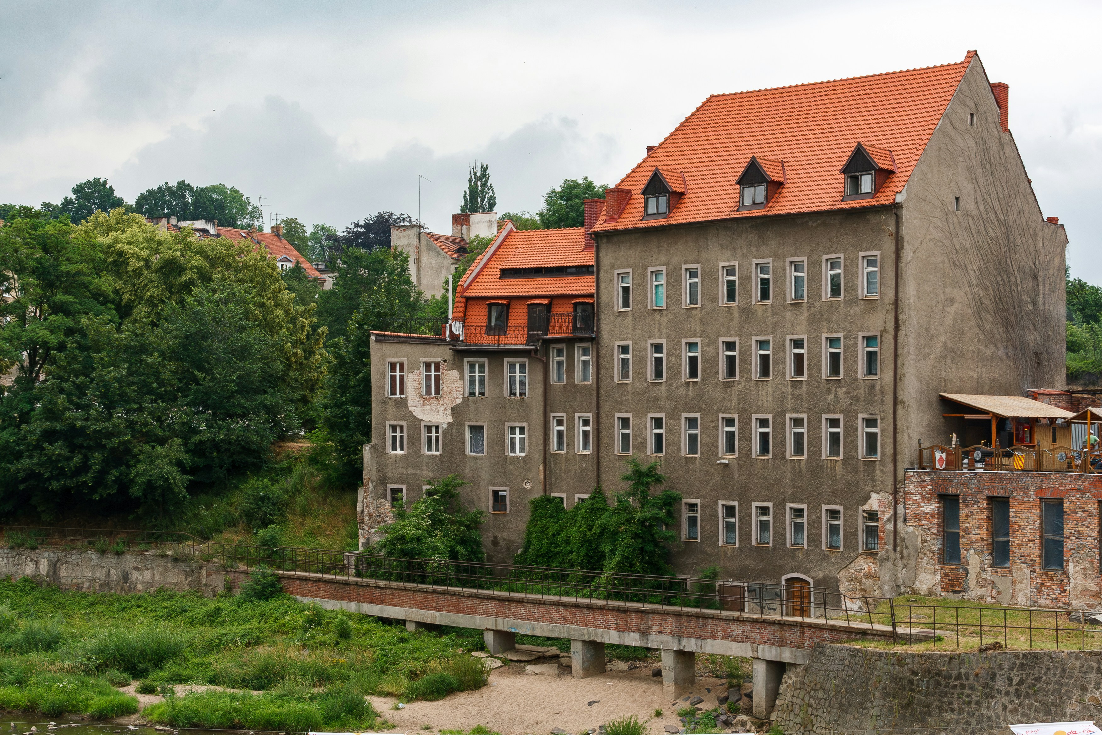 Riverside Facade: A Row of Red-Tiled Homes Beside a Weathered Brick Building