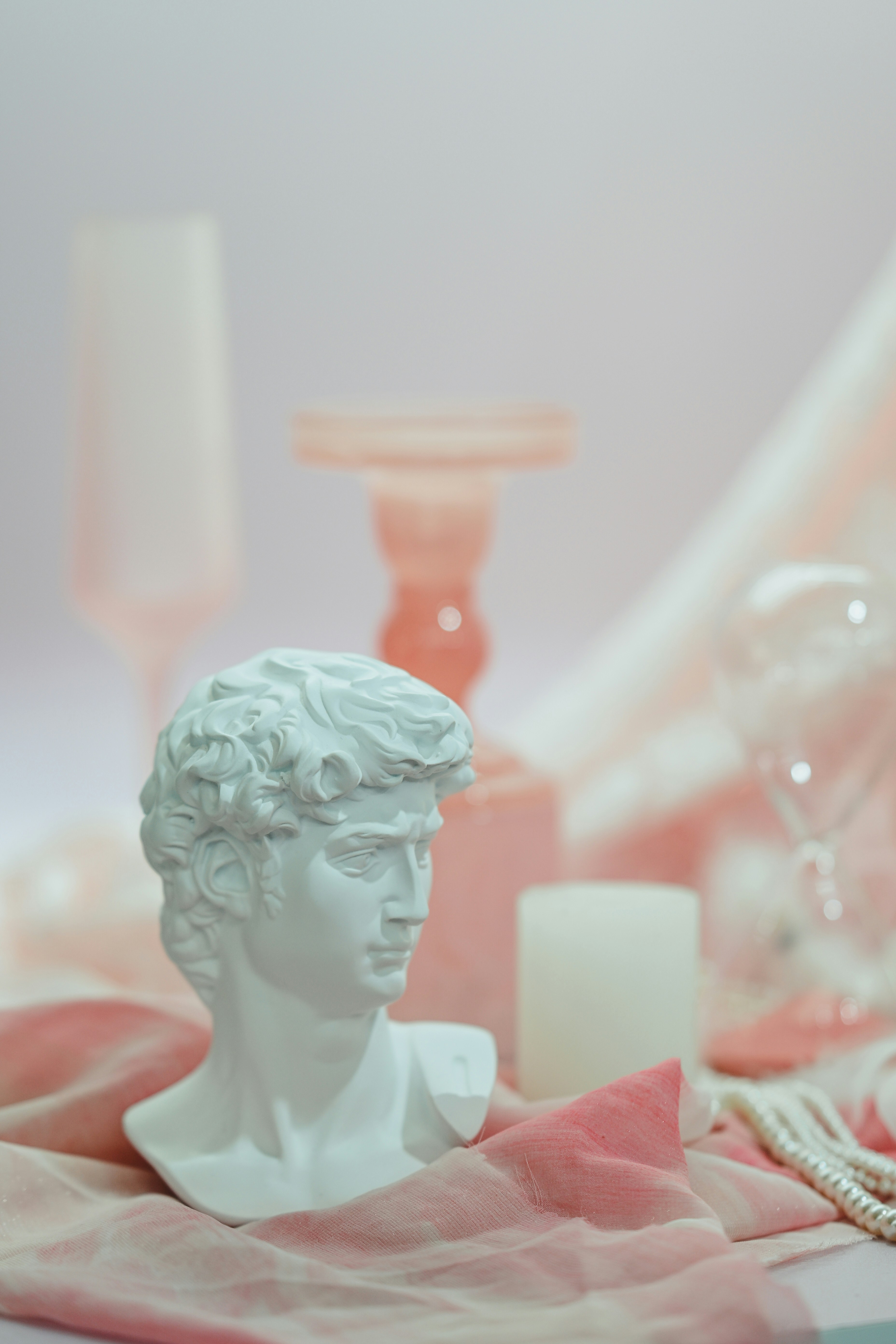 White classical bust amid pastel glow and candlelight setup
