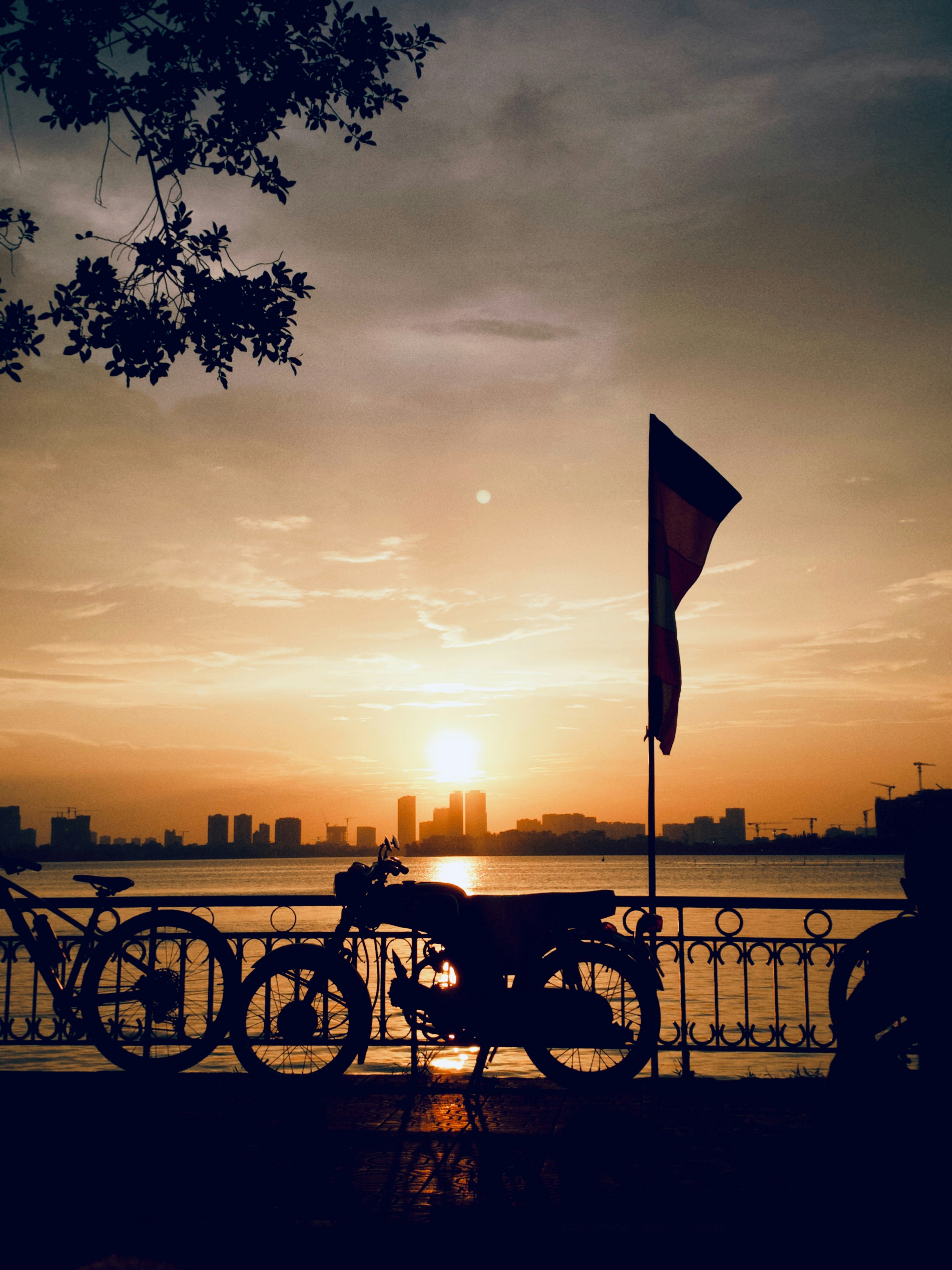Sunset Silhouette by the Riverfront: Bicycles and Flag in Quiet Glow