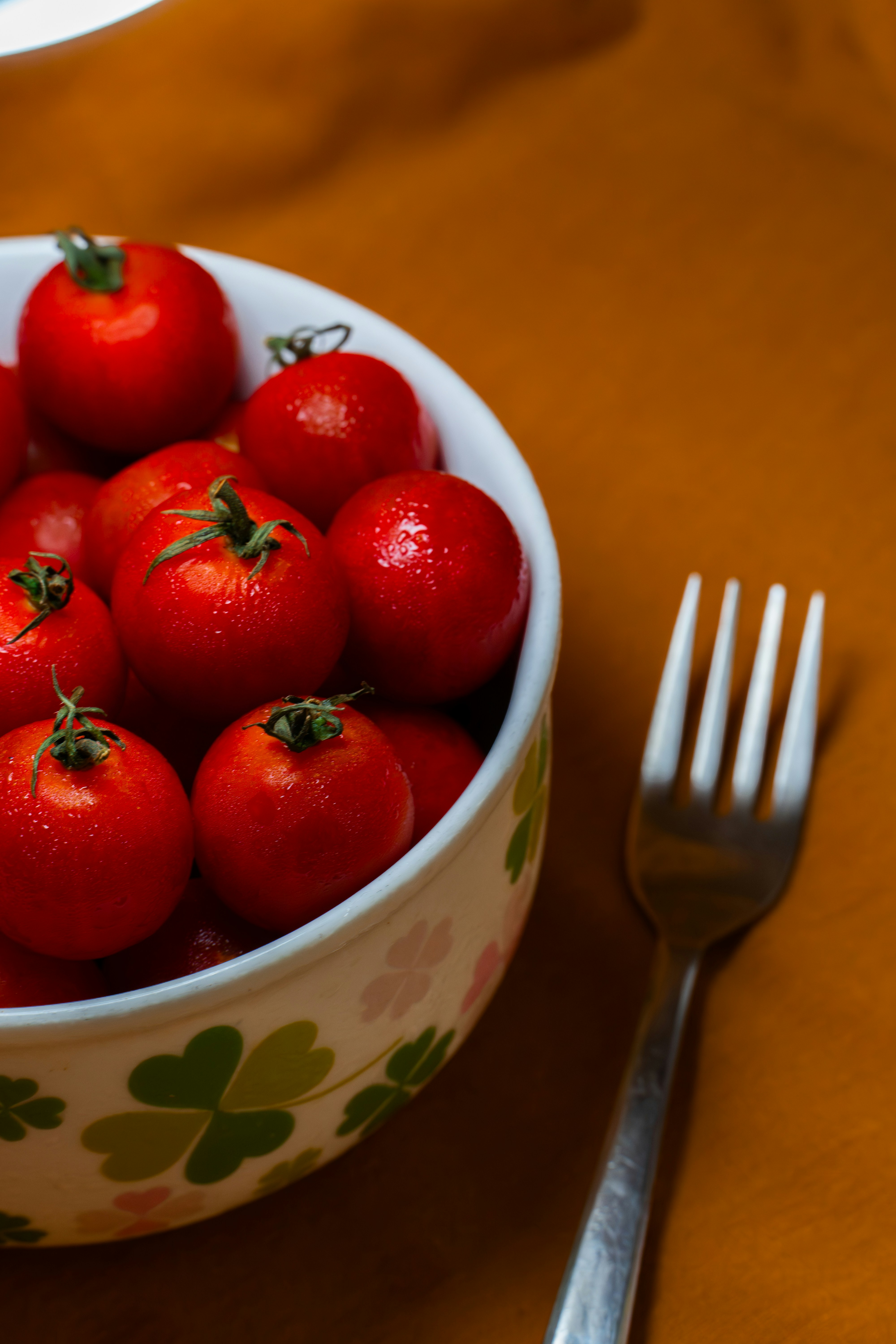 Red Bowl of Tomatoes on a Golden Table with Silver Fork