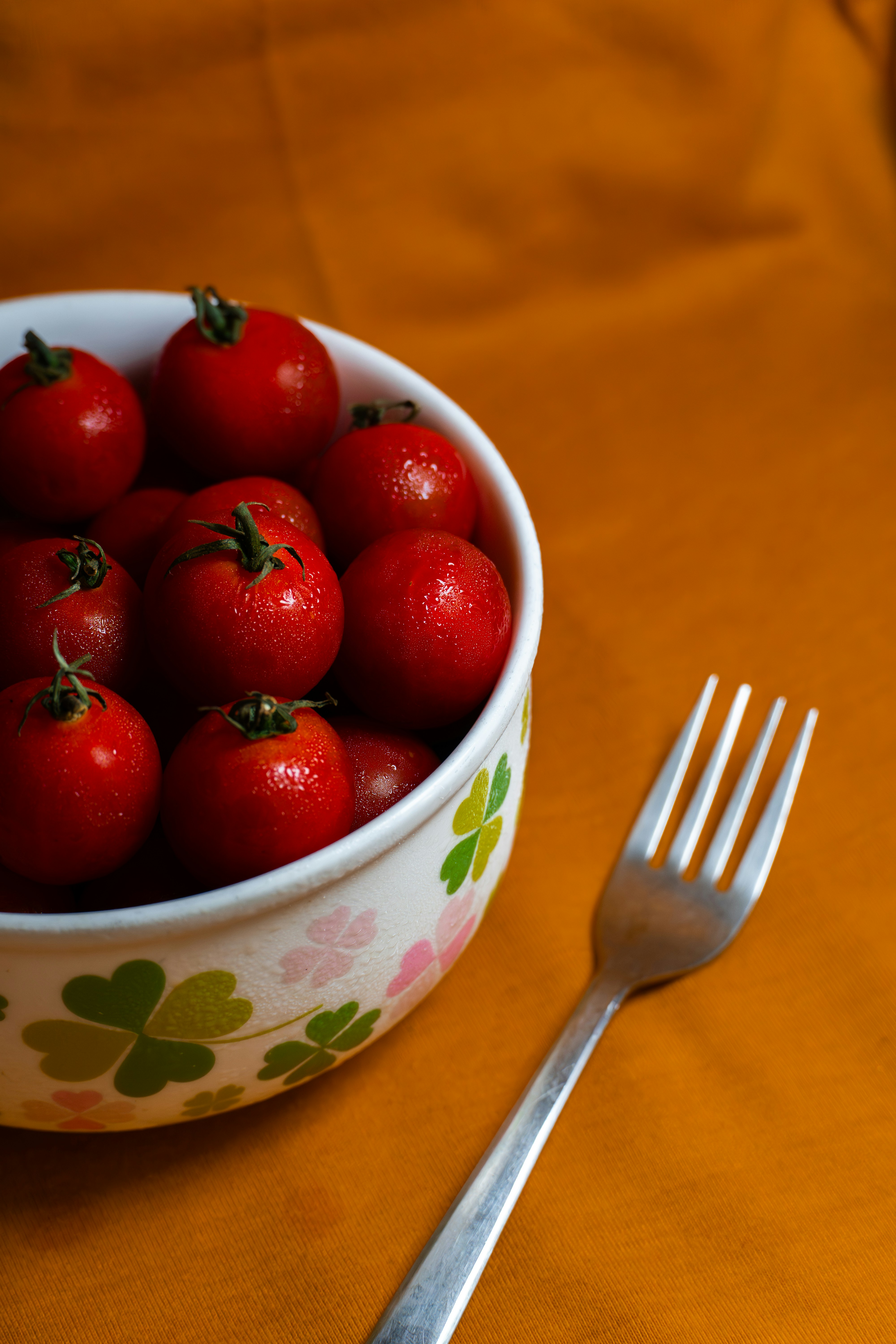 Fresh red cherry tomatoes in a bowl with a fork.
