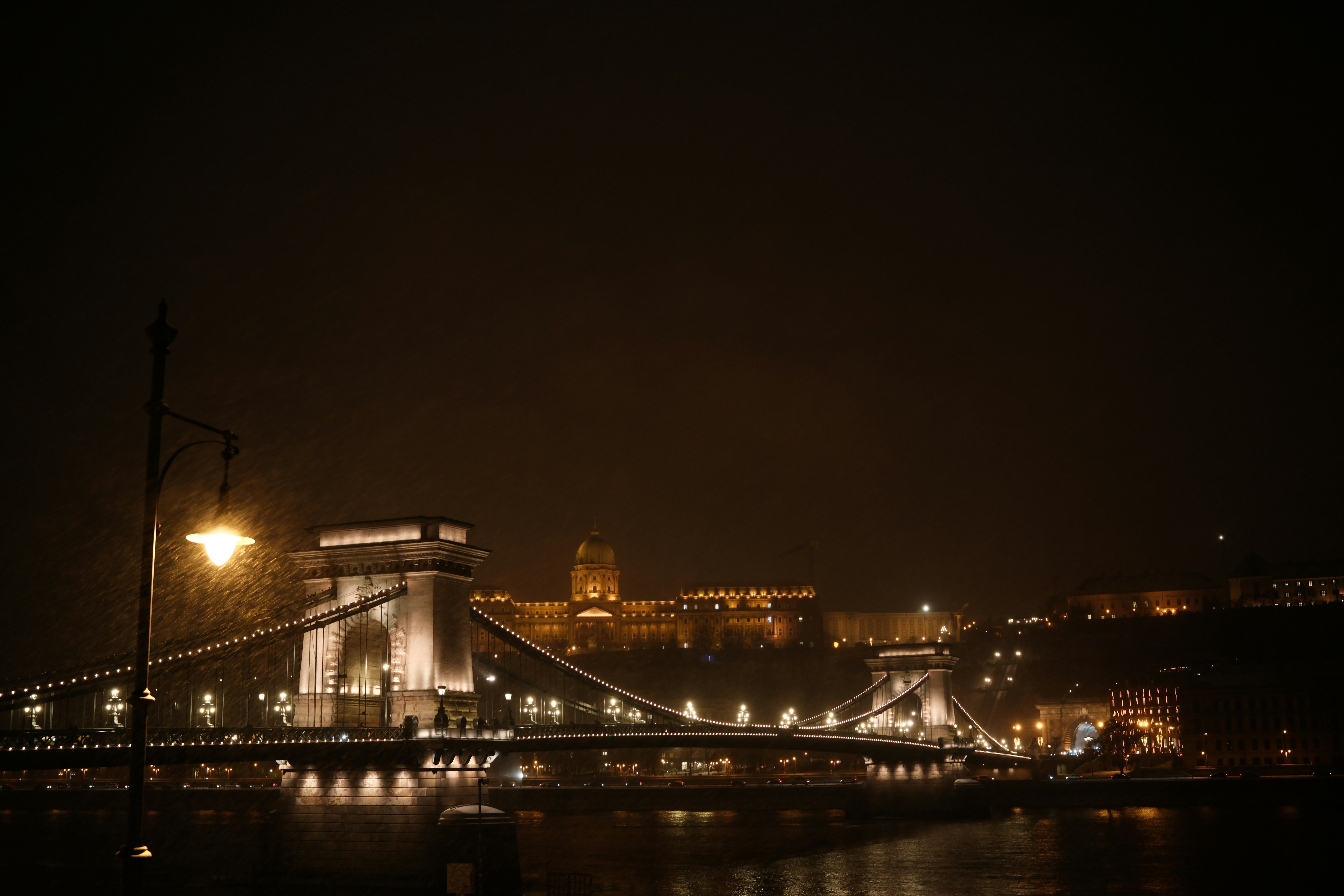 Nightfall over the illuminated chain bridge and riverbank