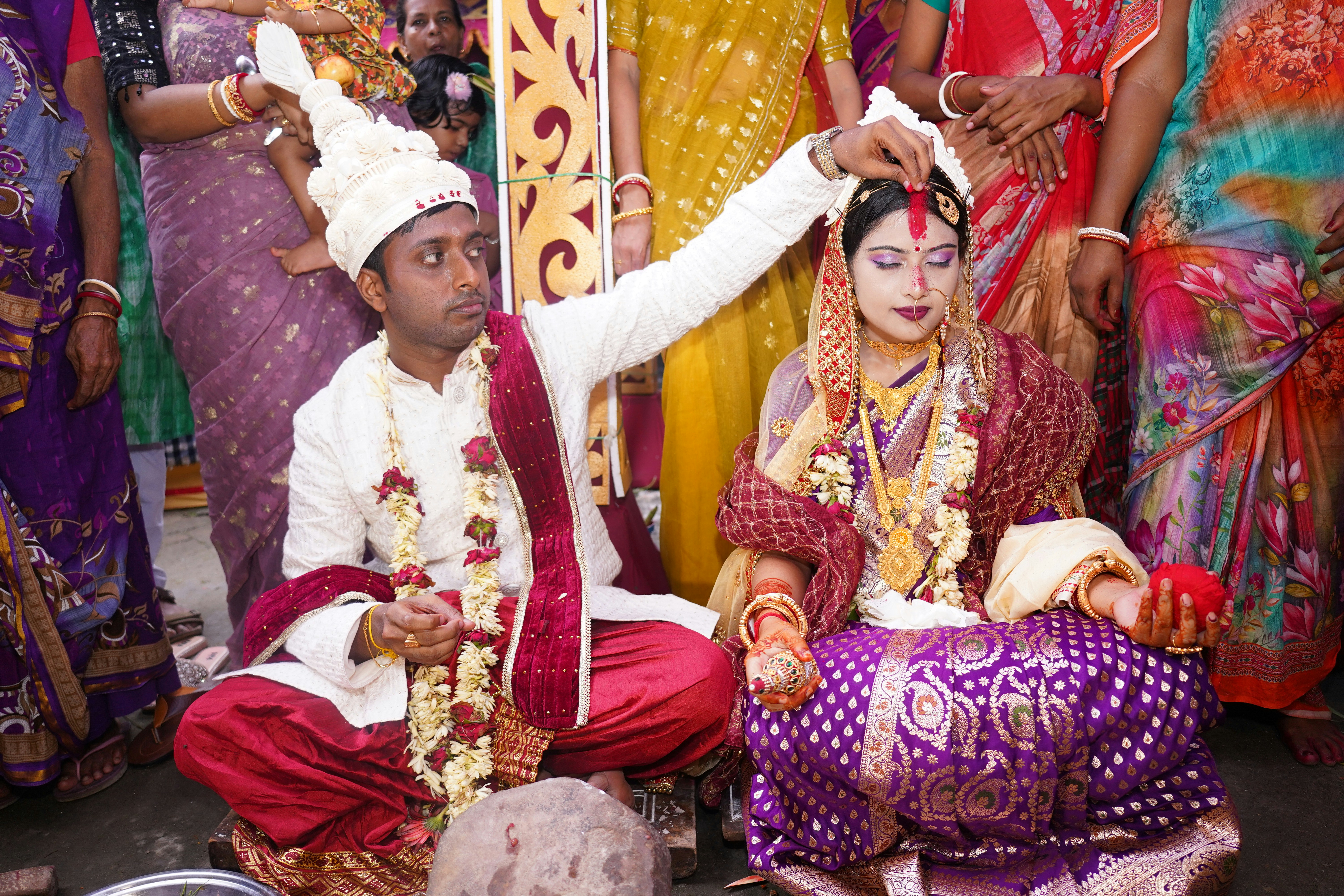 Sinful Saffron: A Bride and Groom Amid Colorful Blessings