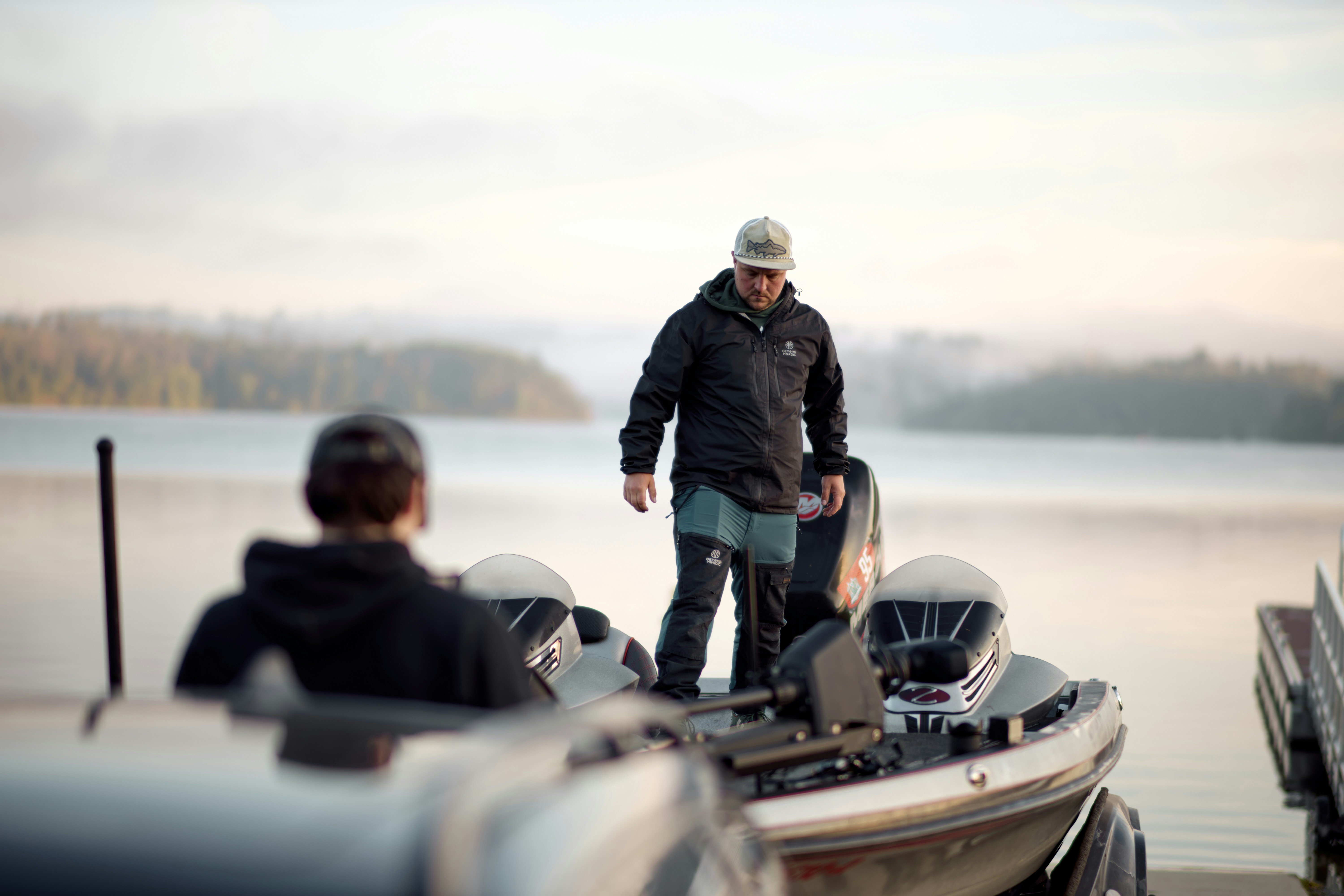 Two men launching a boat into a misty lake.