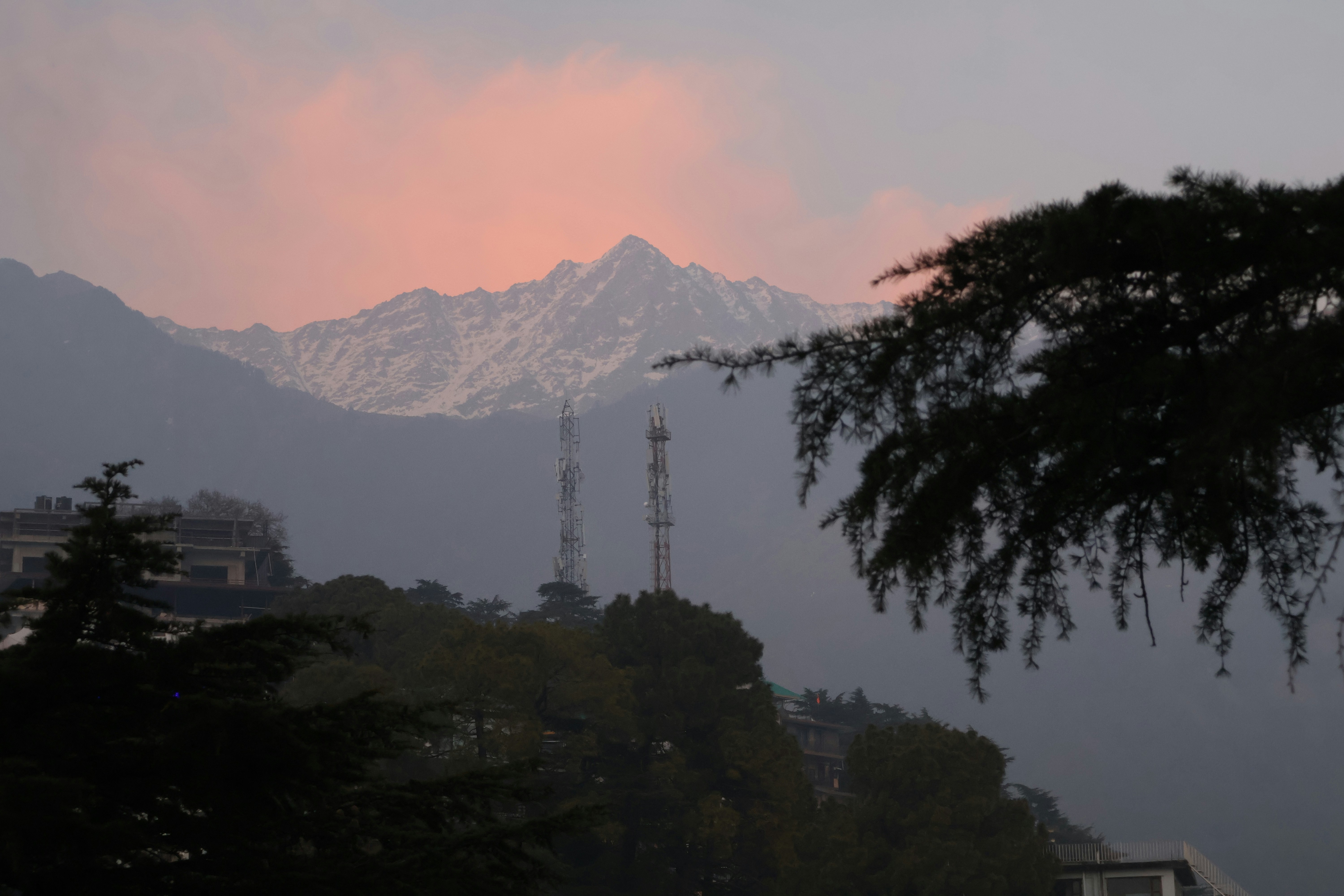 Dawn Over the Valley: Snow-Capped Peak Bathed in Soft Pink Light
