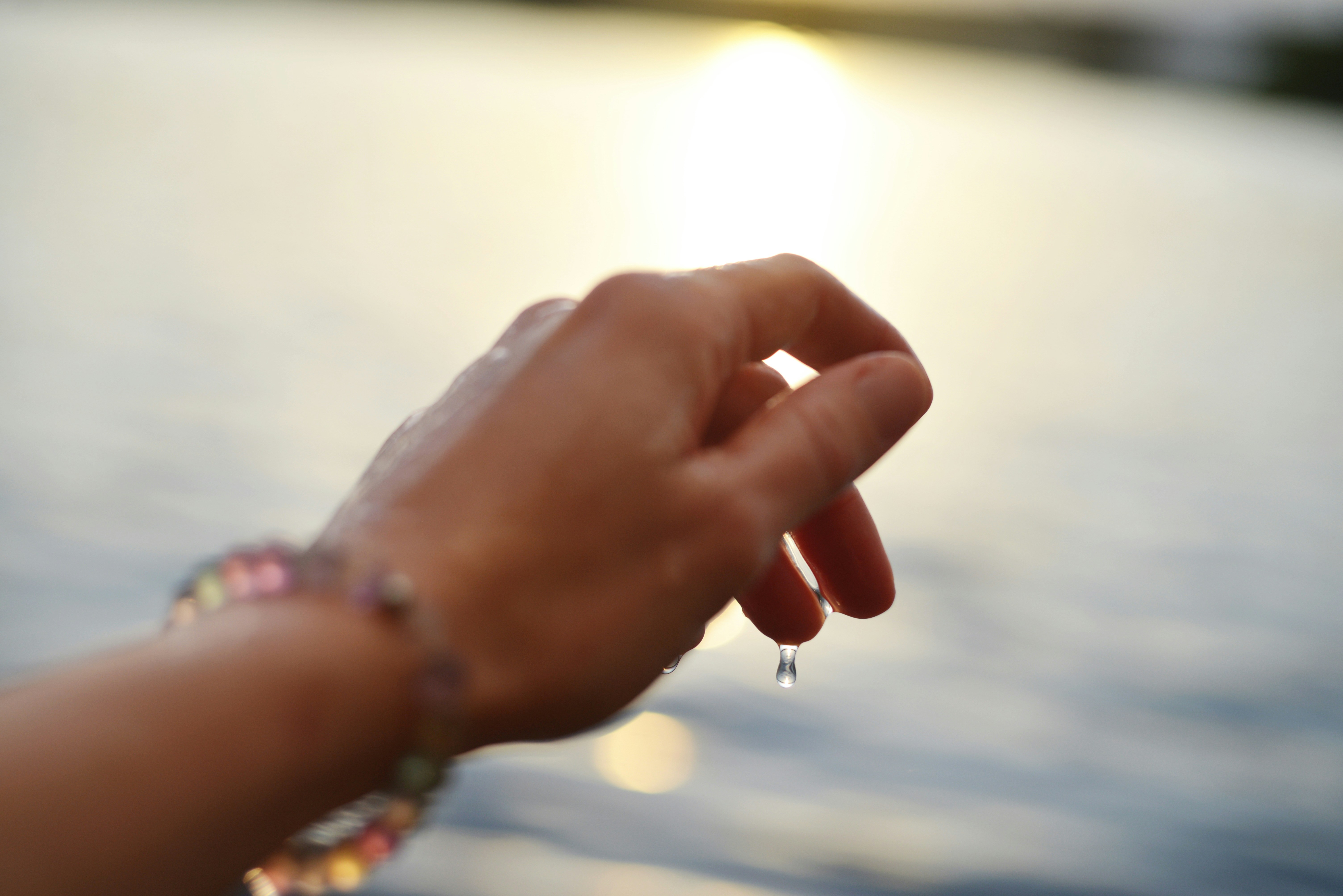 Droplet at the Edge: A Delicate Hand Reaches for a Sunset Tear