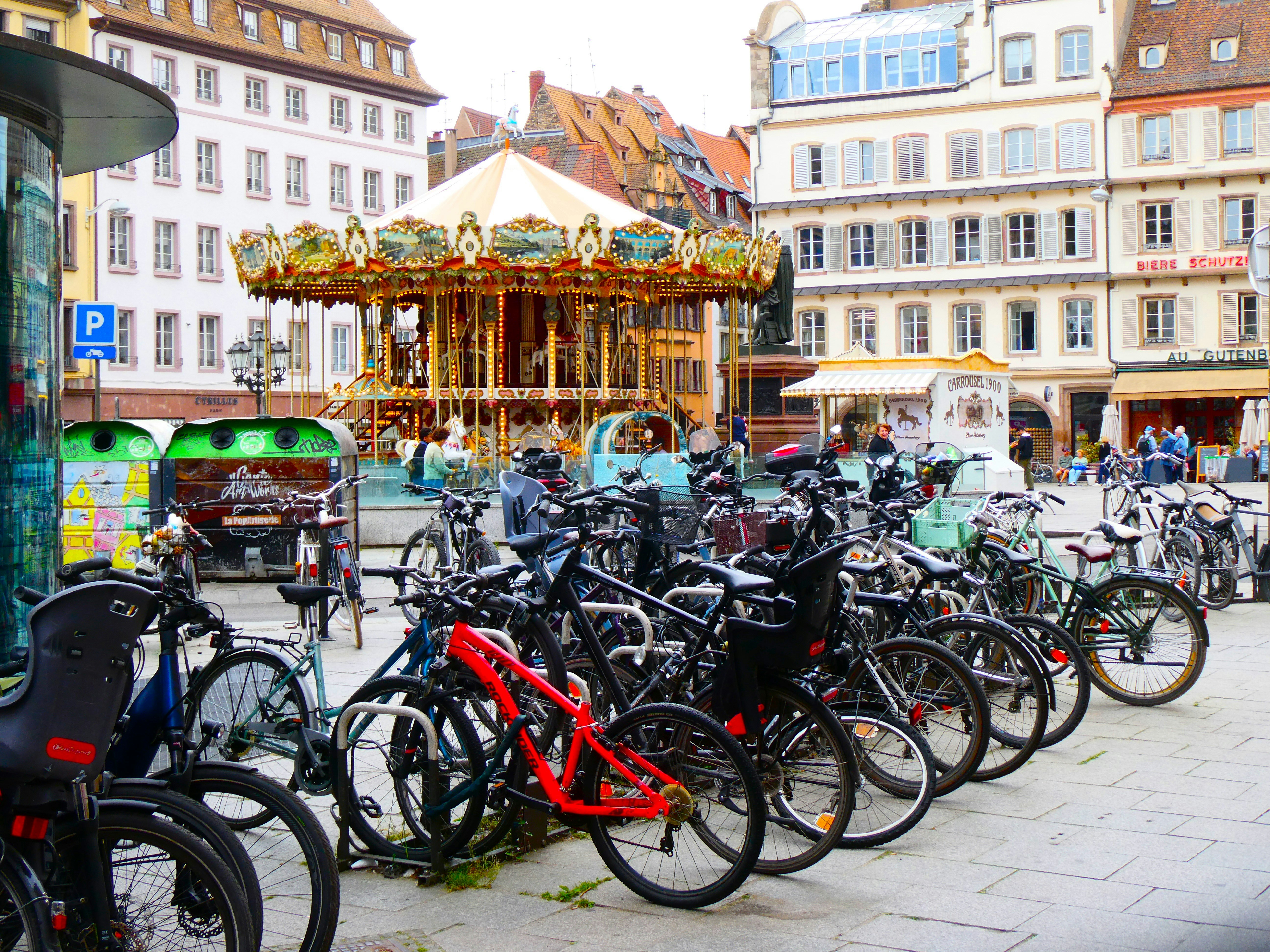 A long row of bicycles parked in front of a merry-go-round in the middle of a city