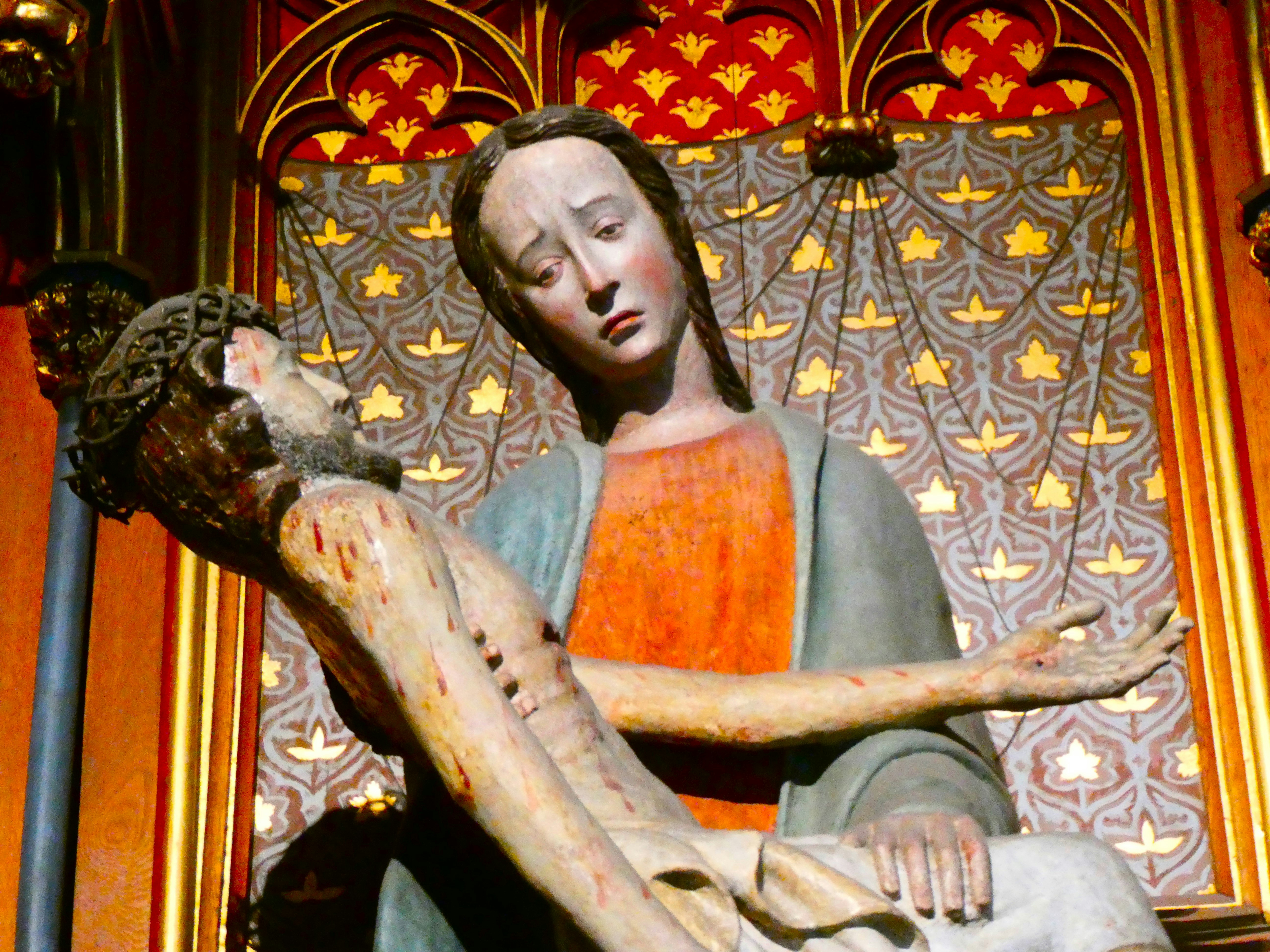 The Blessed Burden: A Stately Carved Madonna Cradling a Contorted Figure