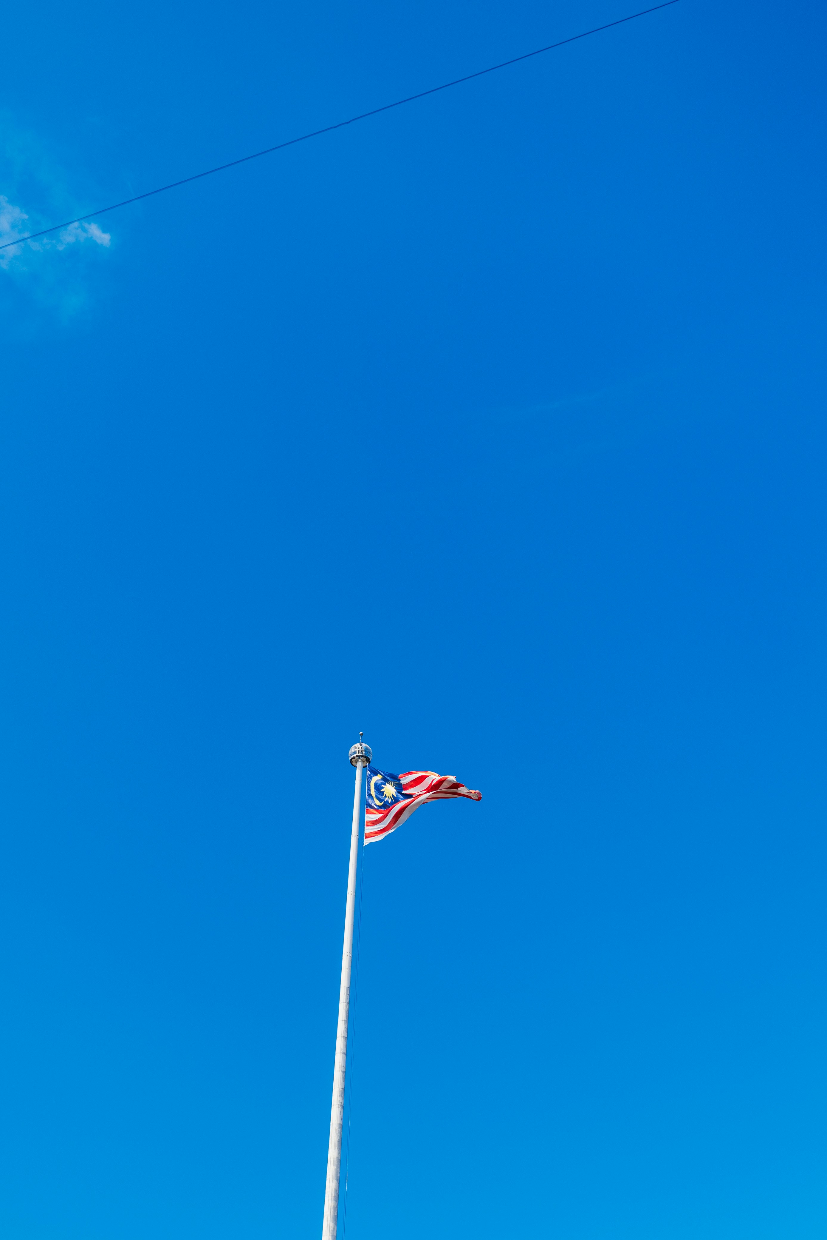 Flag Portrait: A Lone Flagpole Pierces a Clear Blue Sky