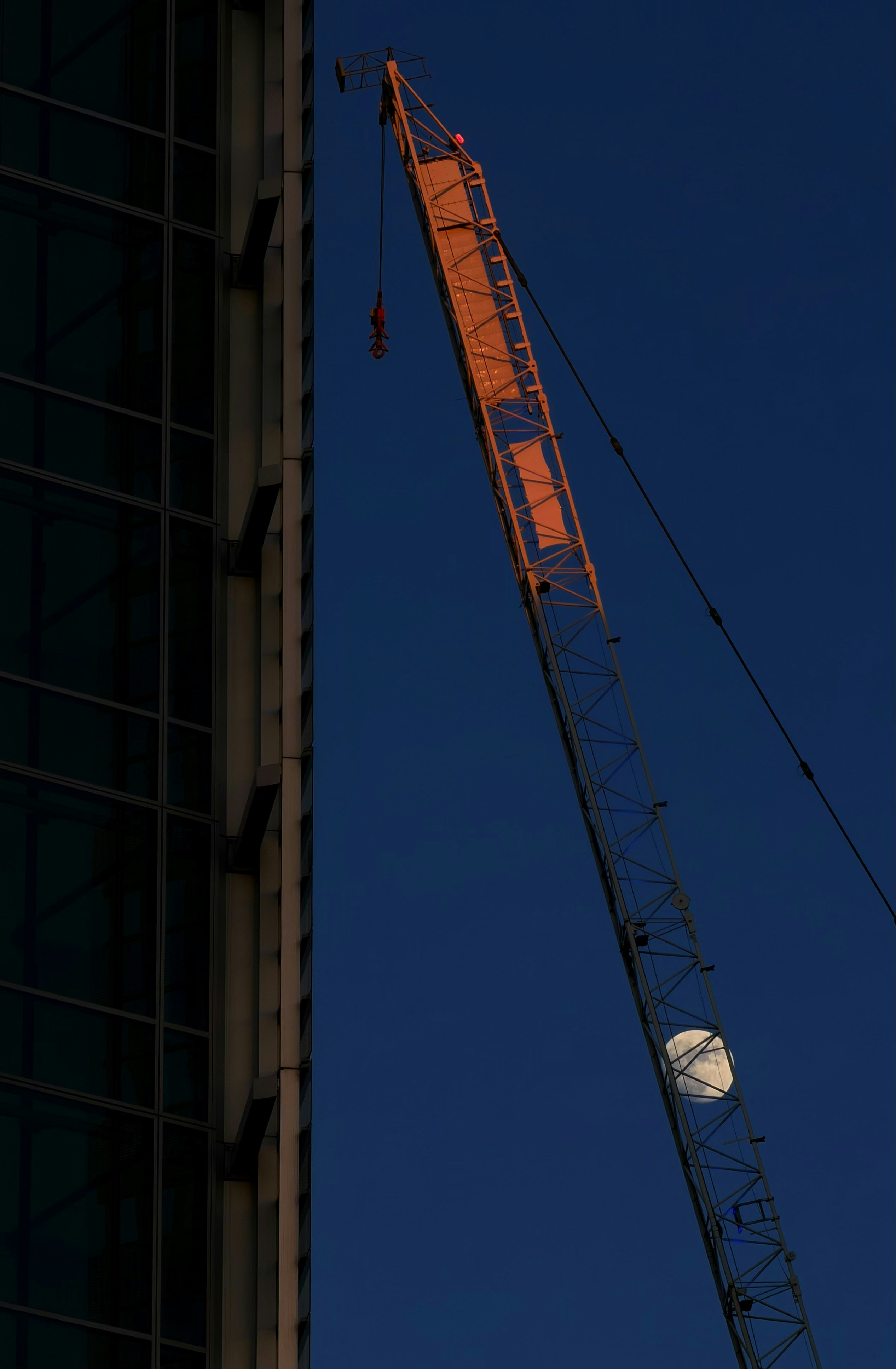 Crane Arc Over a Modern Facade at Dusk