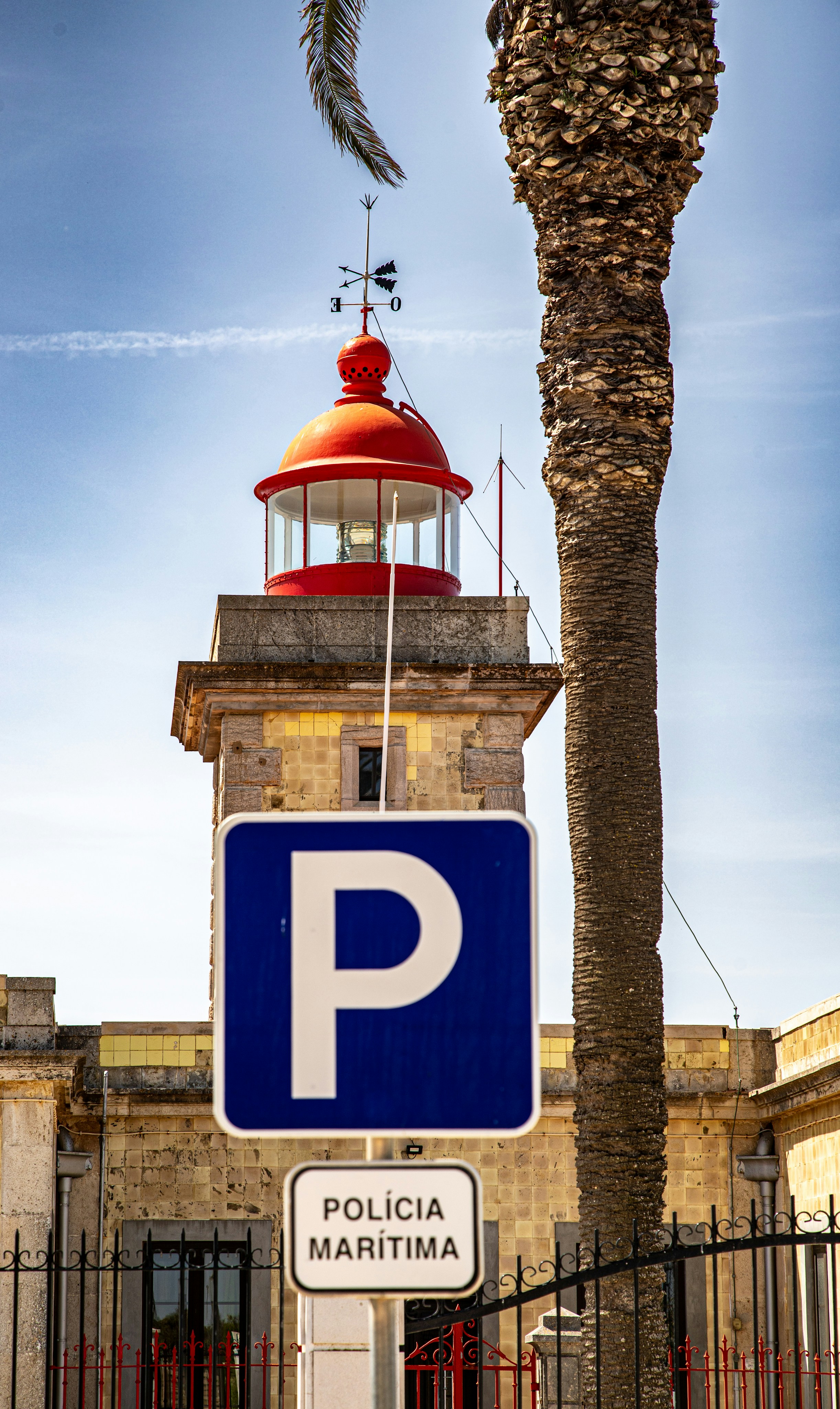 Lighthouse Turret and Parking Sign Under Palm in Sunlit Facade