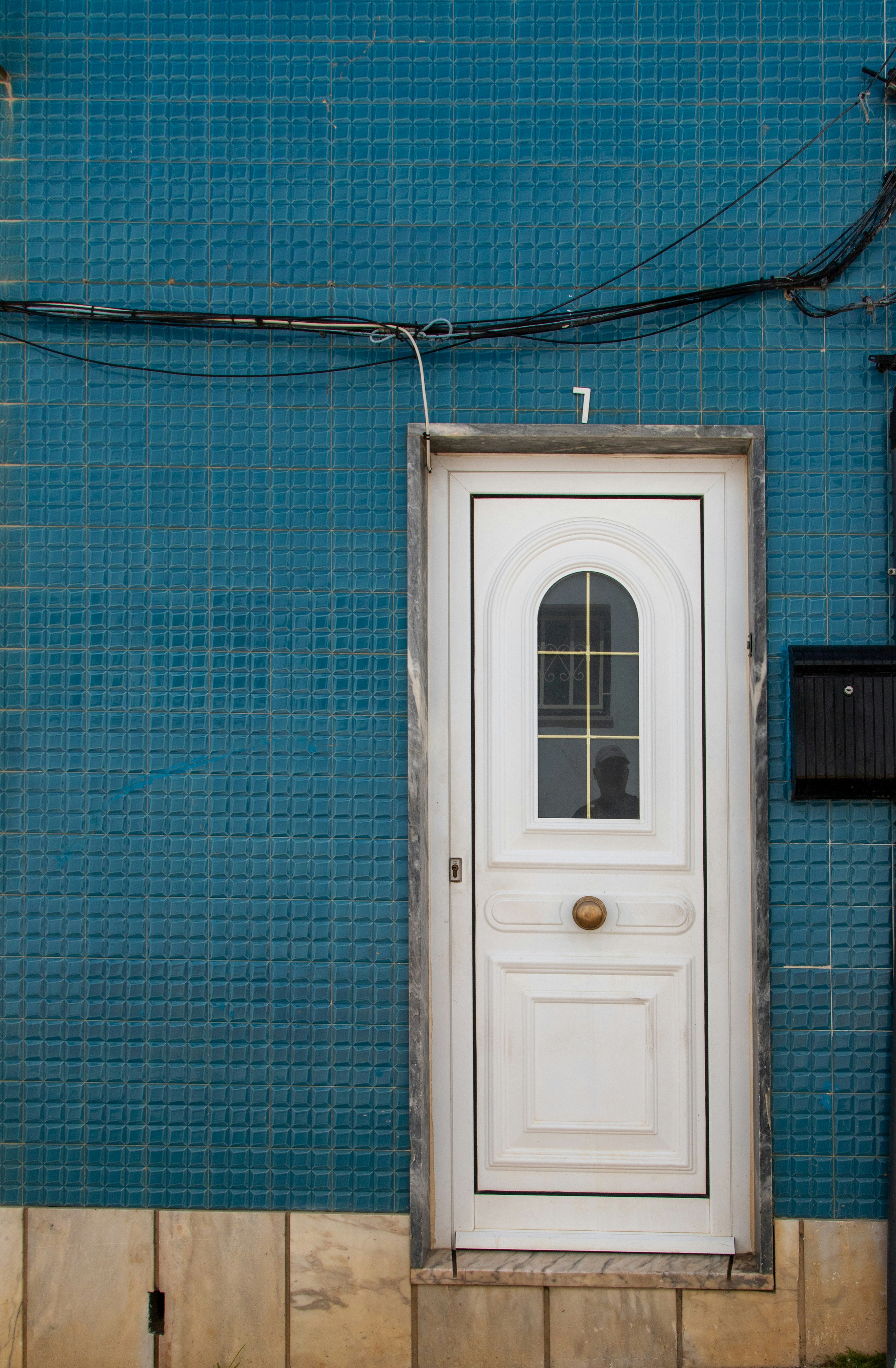 Blue Tile Doorway: A Quiet Urban Facade Framed by Electric Cables