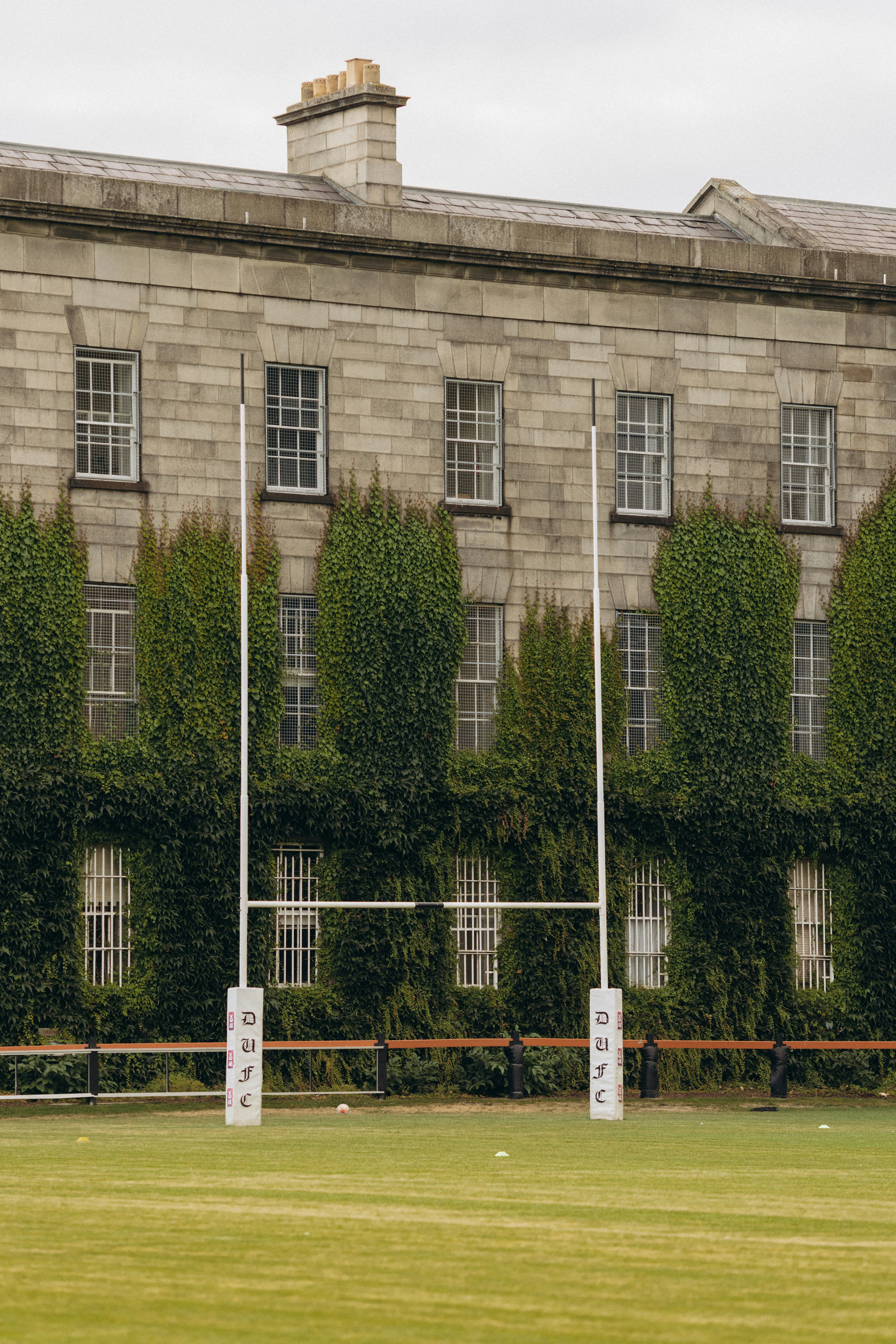 Goalposts Beneath a Ivy-Clad Facade